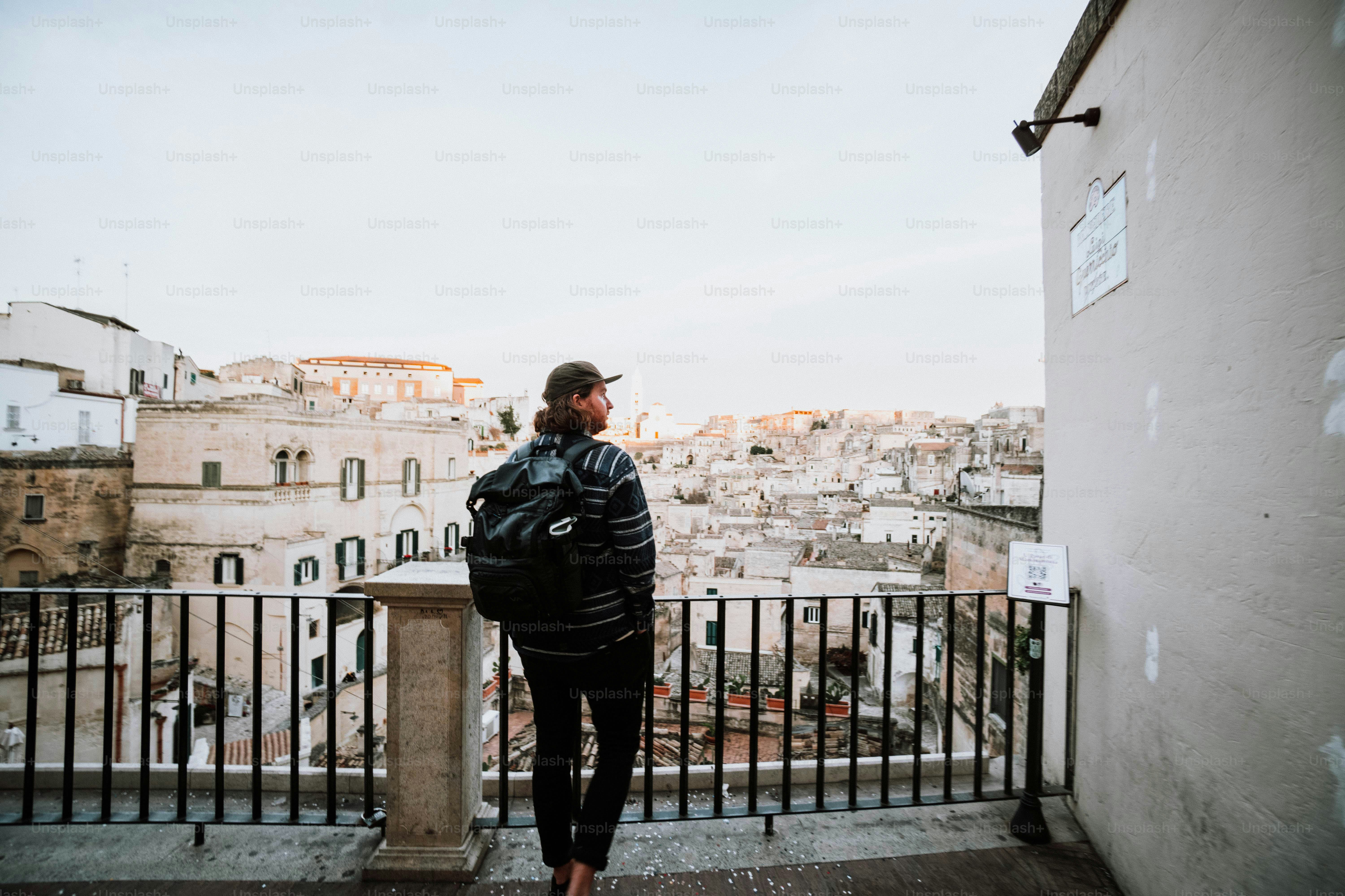 A man standing on a balcony overlooking a city photo – Touristic place ...