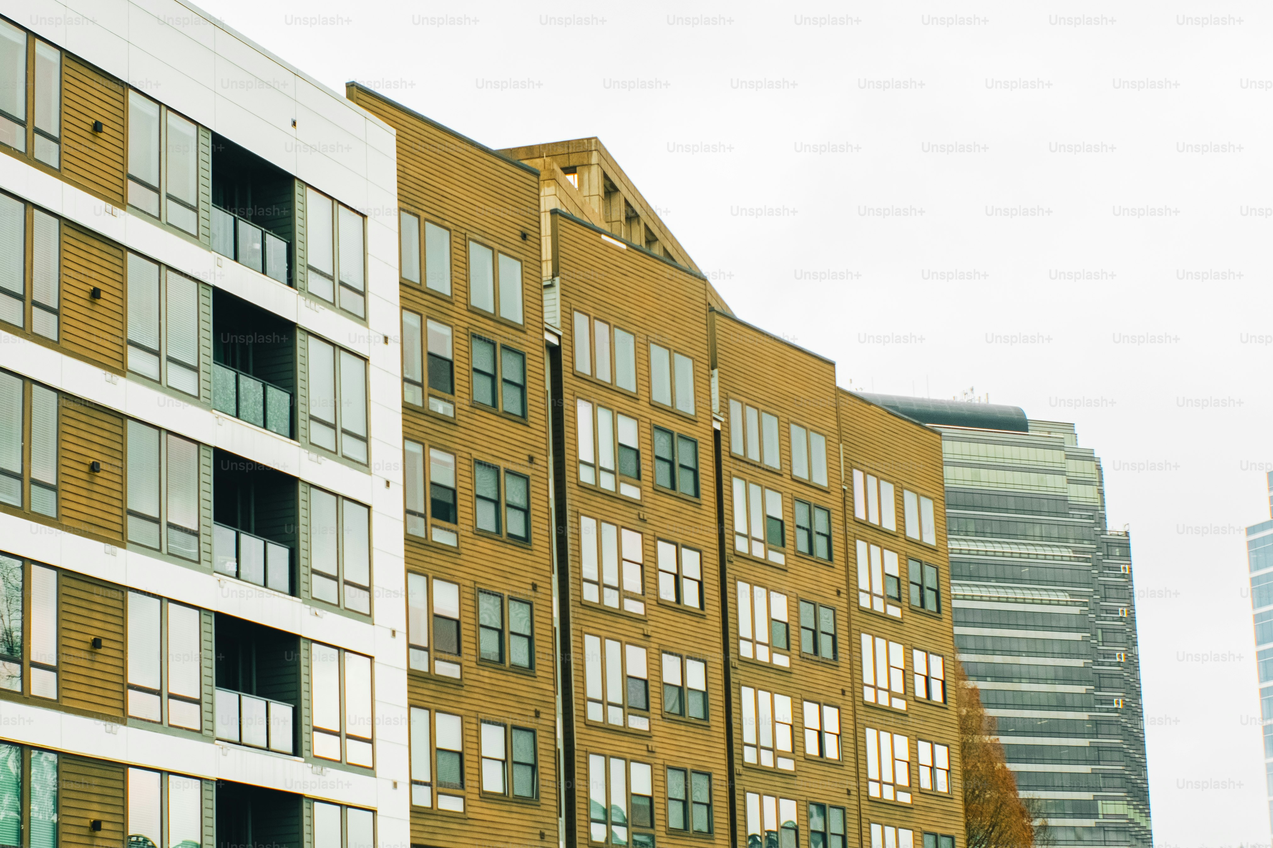 A tall building with lots of windows next to other buildings photo ...