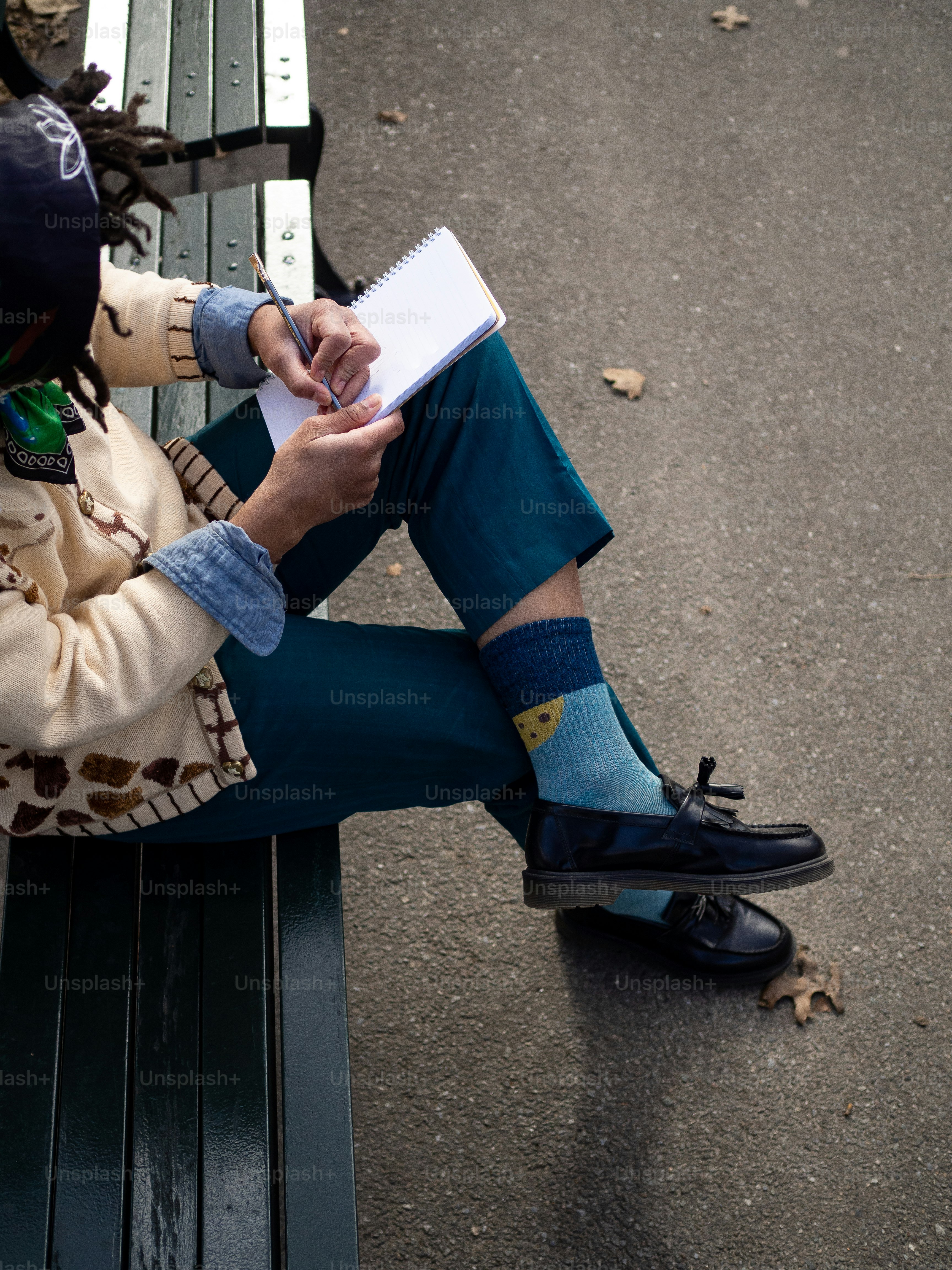 A person sitting on a bench writing on a piece of paper photo ...