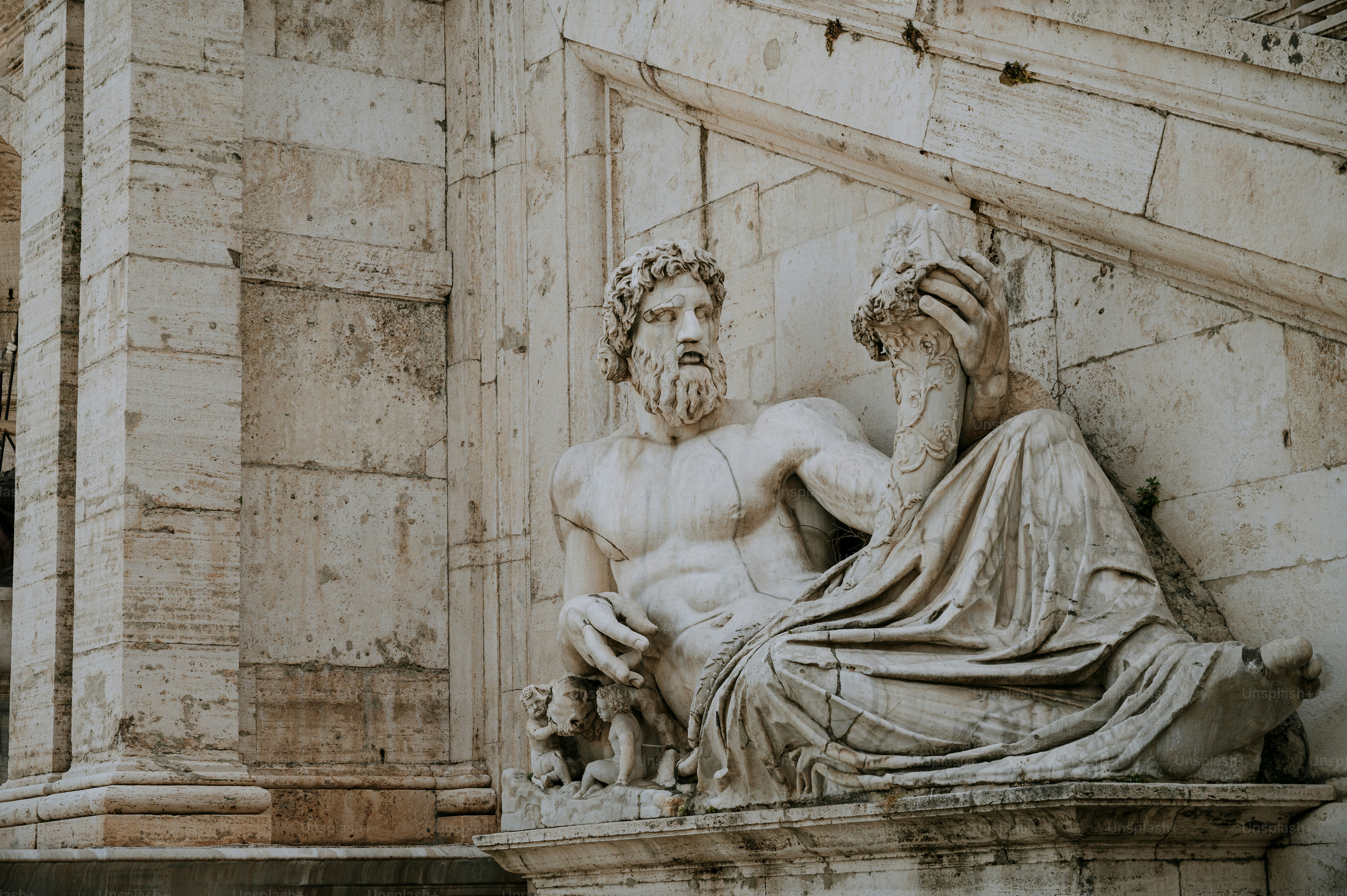 A statue of a man with a beard sitting on a ledge photo – Rome Image on ...