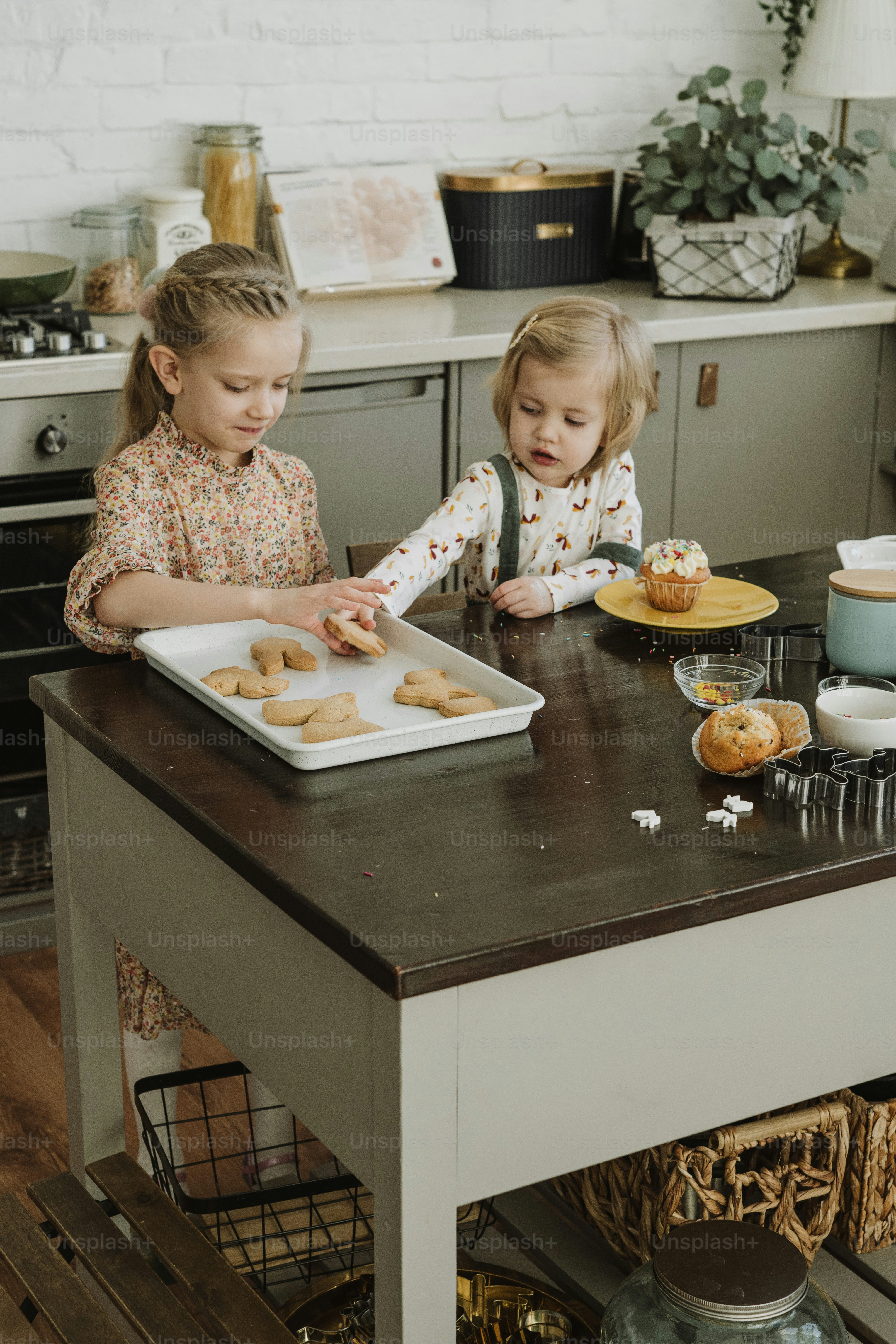 Two little girls sitting at a kitchen table photo – Baking Image on ...