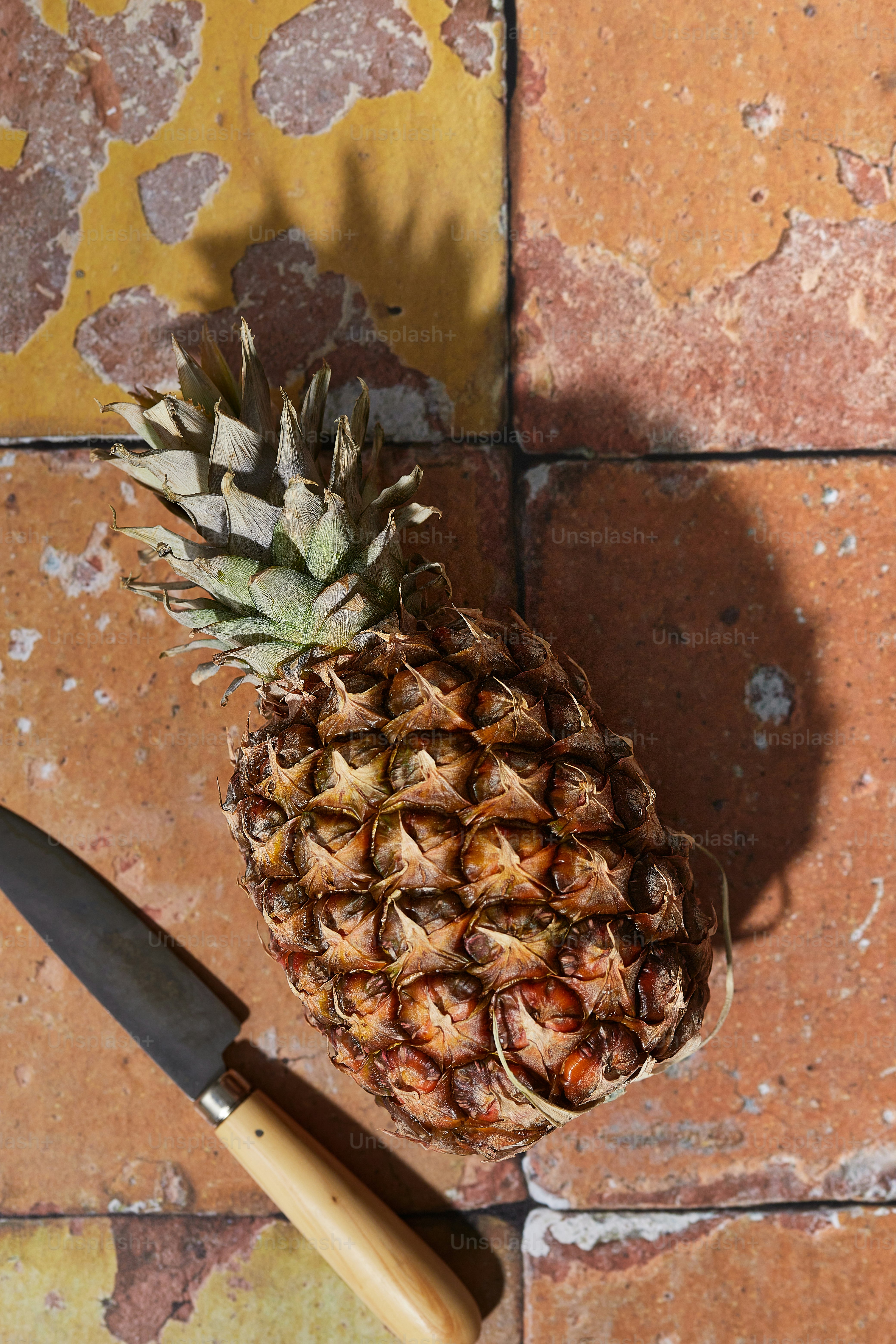 Un ananas assis sur une table à côté d’un couteau photo – Aliments ...