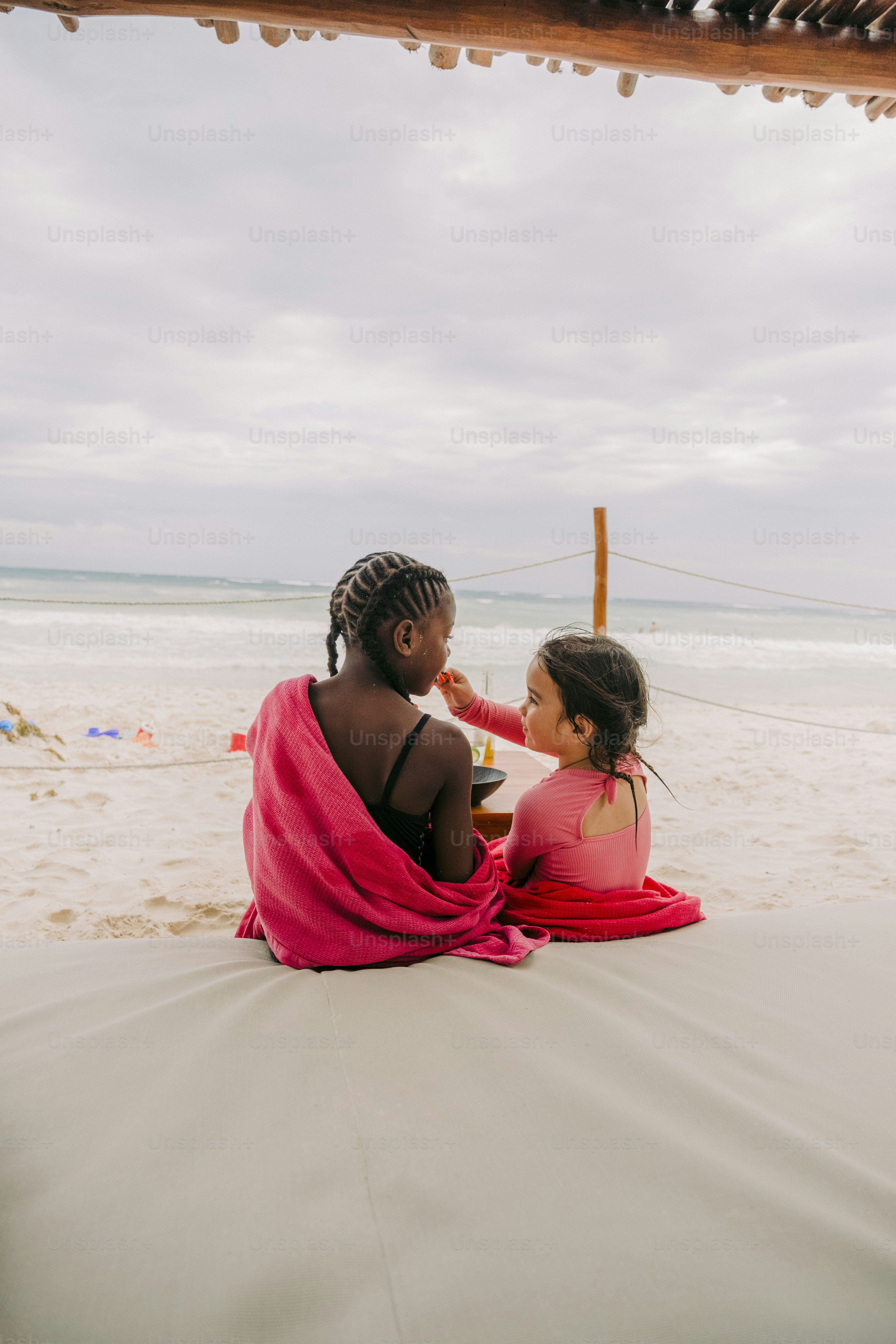 A couple of women sitting on top of a sandy beach photo – Spring break ...