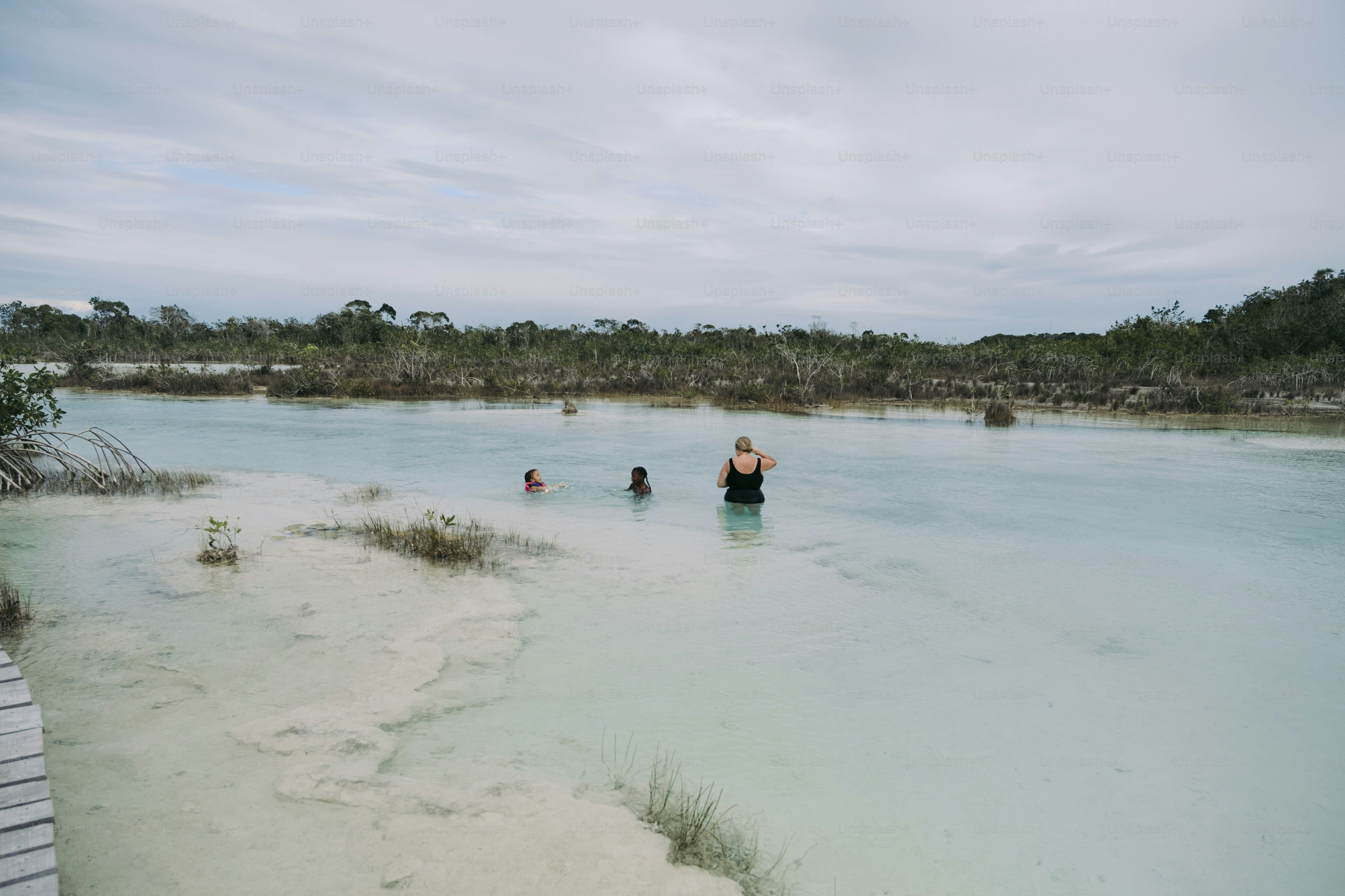 A group of people wading in a body of water photo – Spring break Image ...