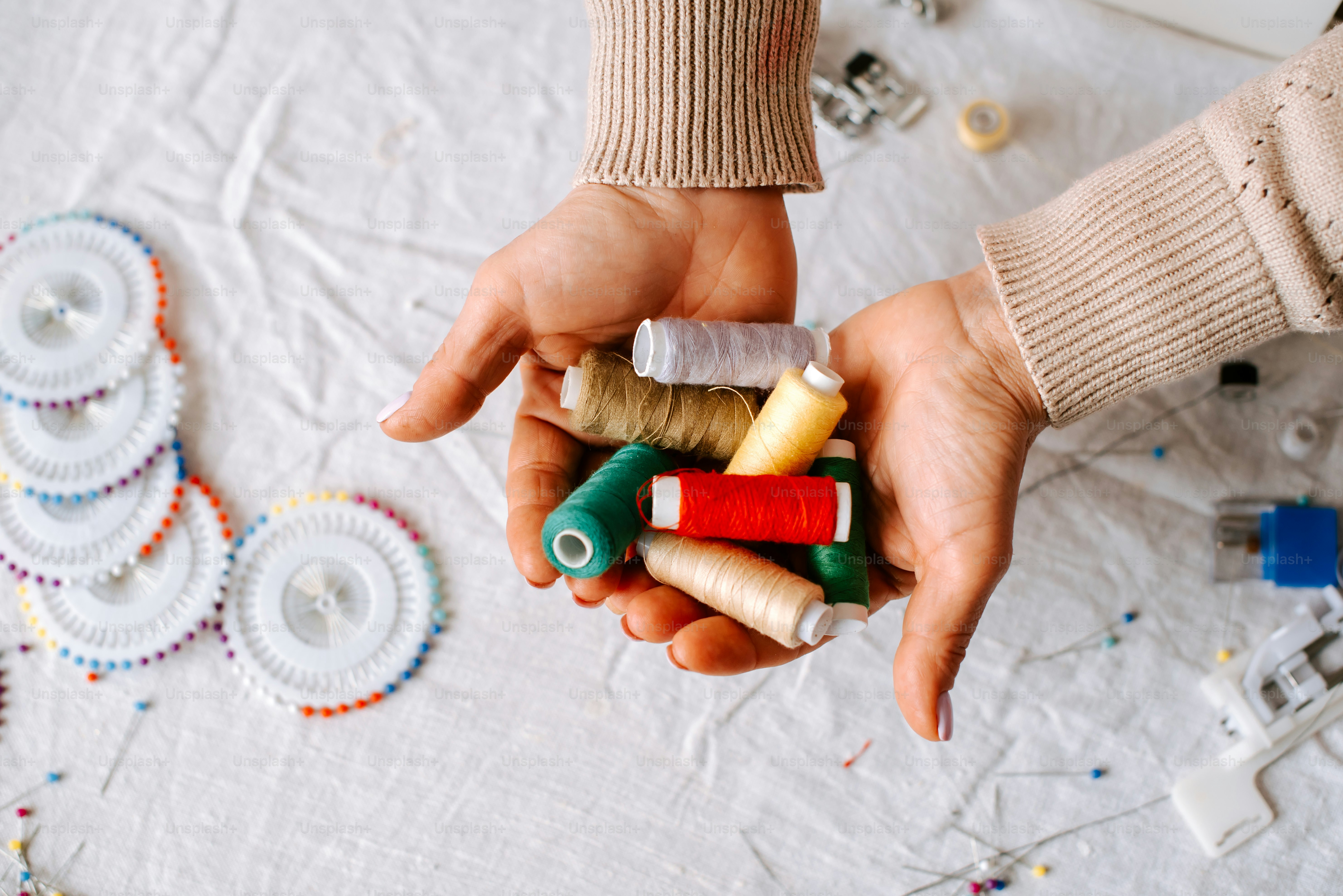 A person holding a bunch of different colored spools of thread photo ...