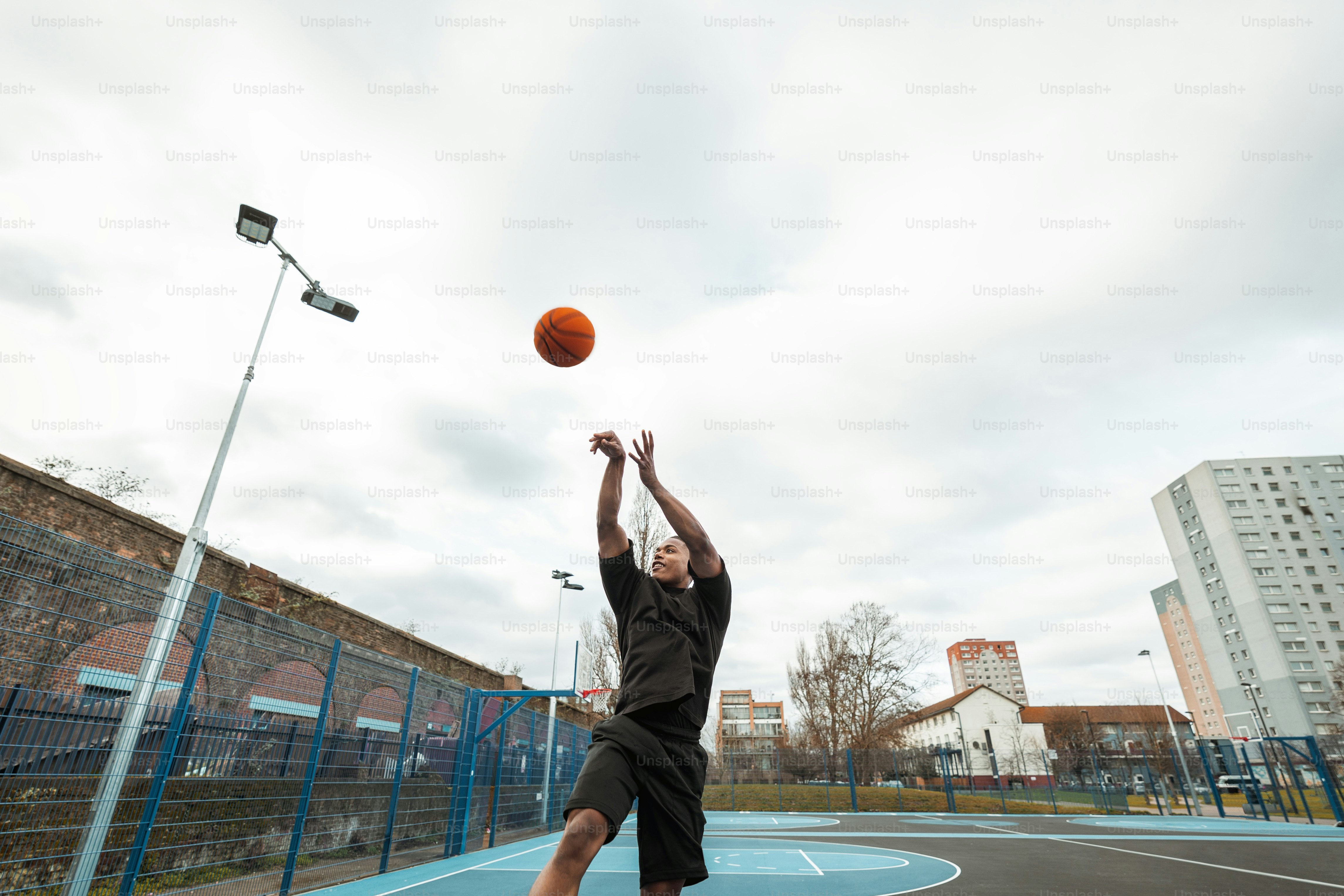 A man is playing basketball on a cloudy day photo – Basketball player ...