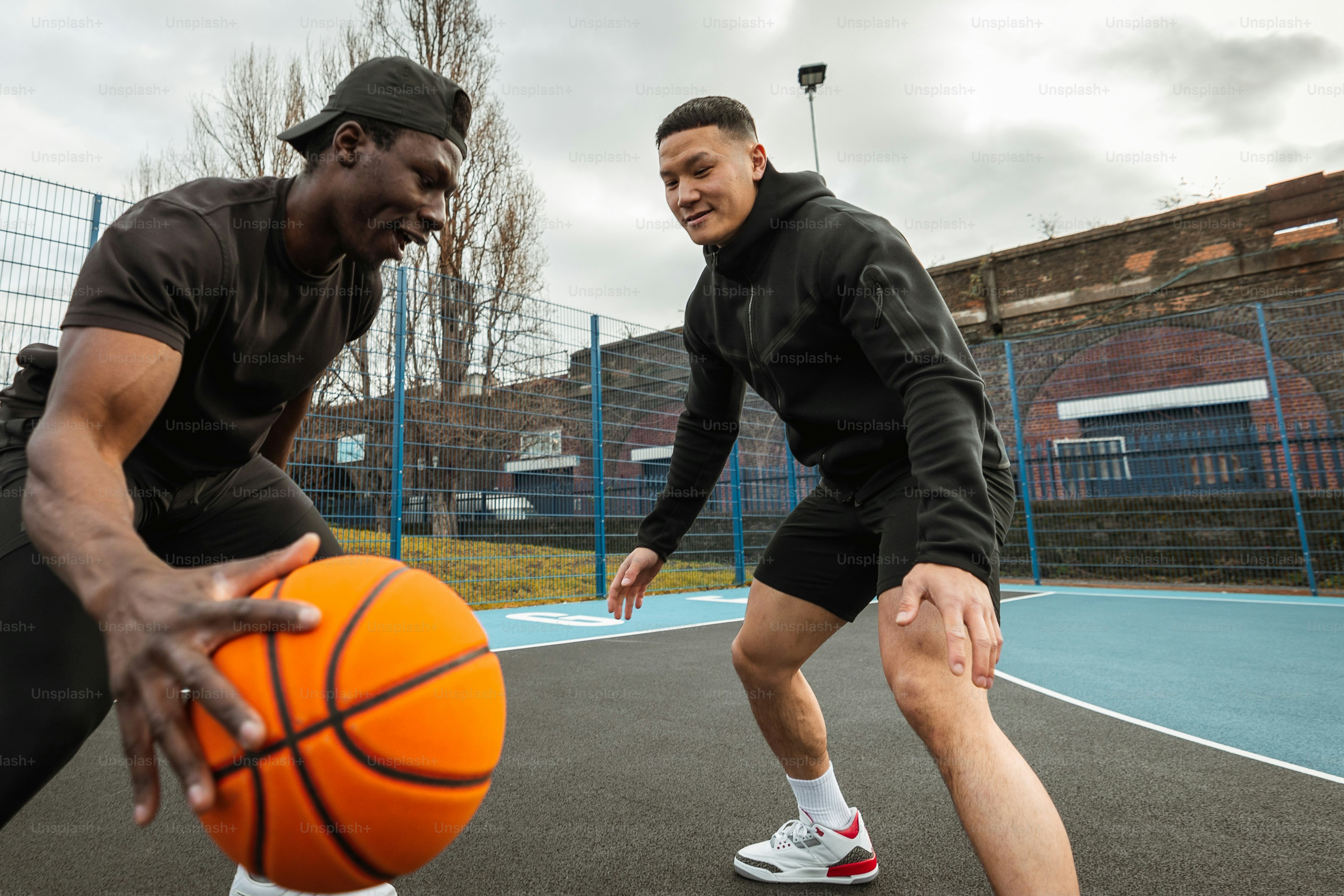 A couple of men standing on top of a basketball court photo – Sports ...