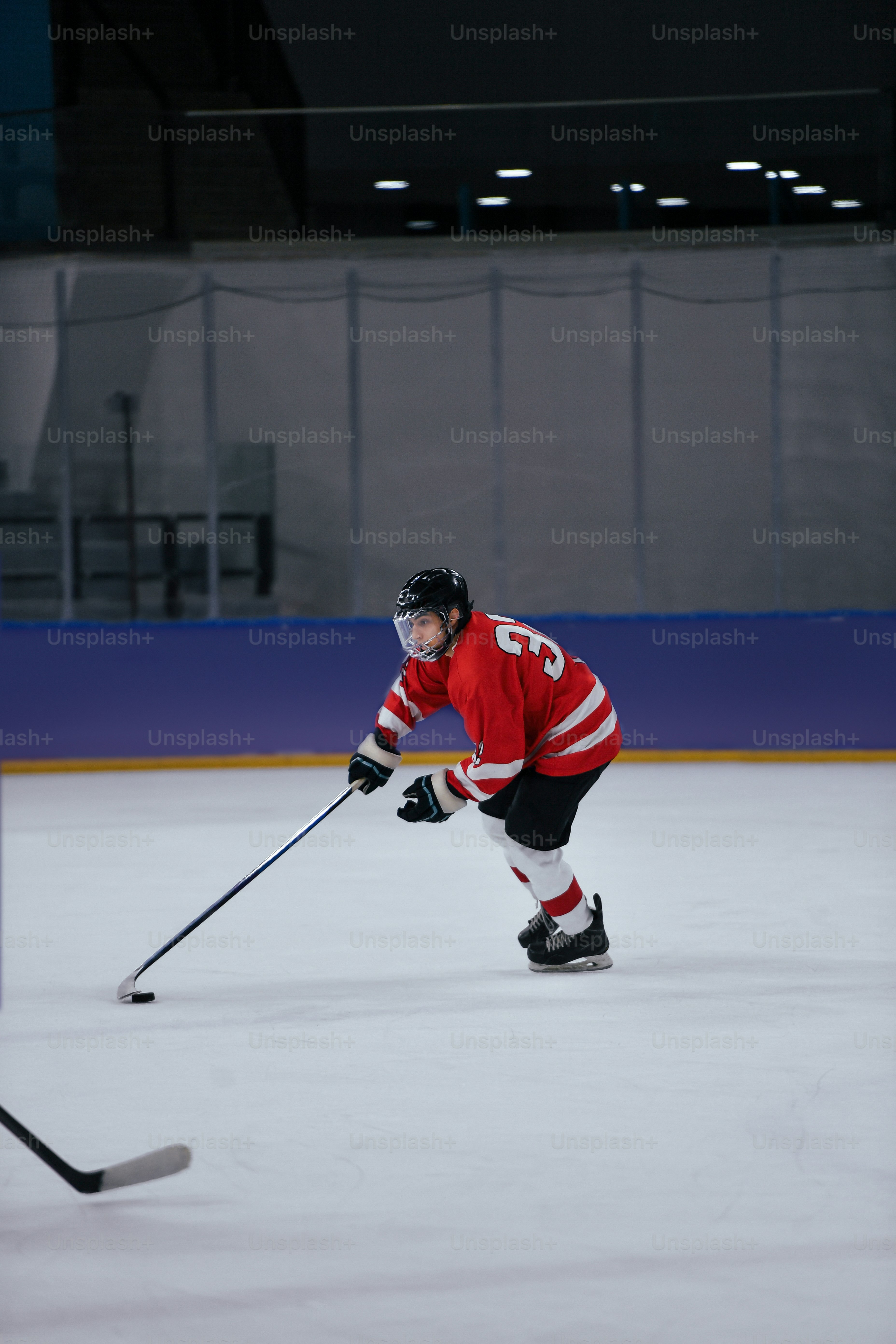 A man in a red jersey skating on an ice rink photo – Ice hockey Image ...