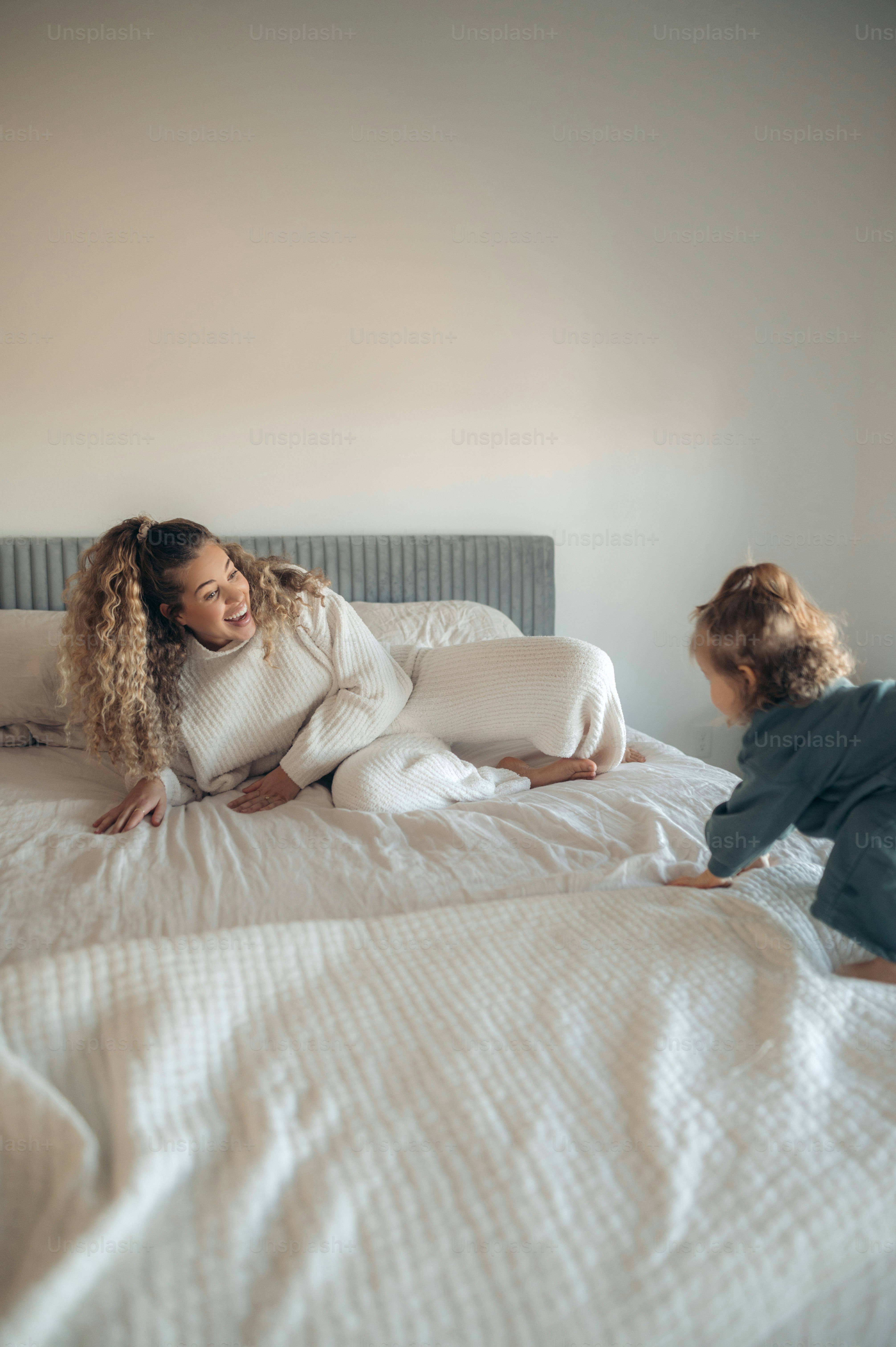 Une femme allongée sur un lit à côté d’un enfant photo – Bébé Photo sur ...