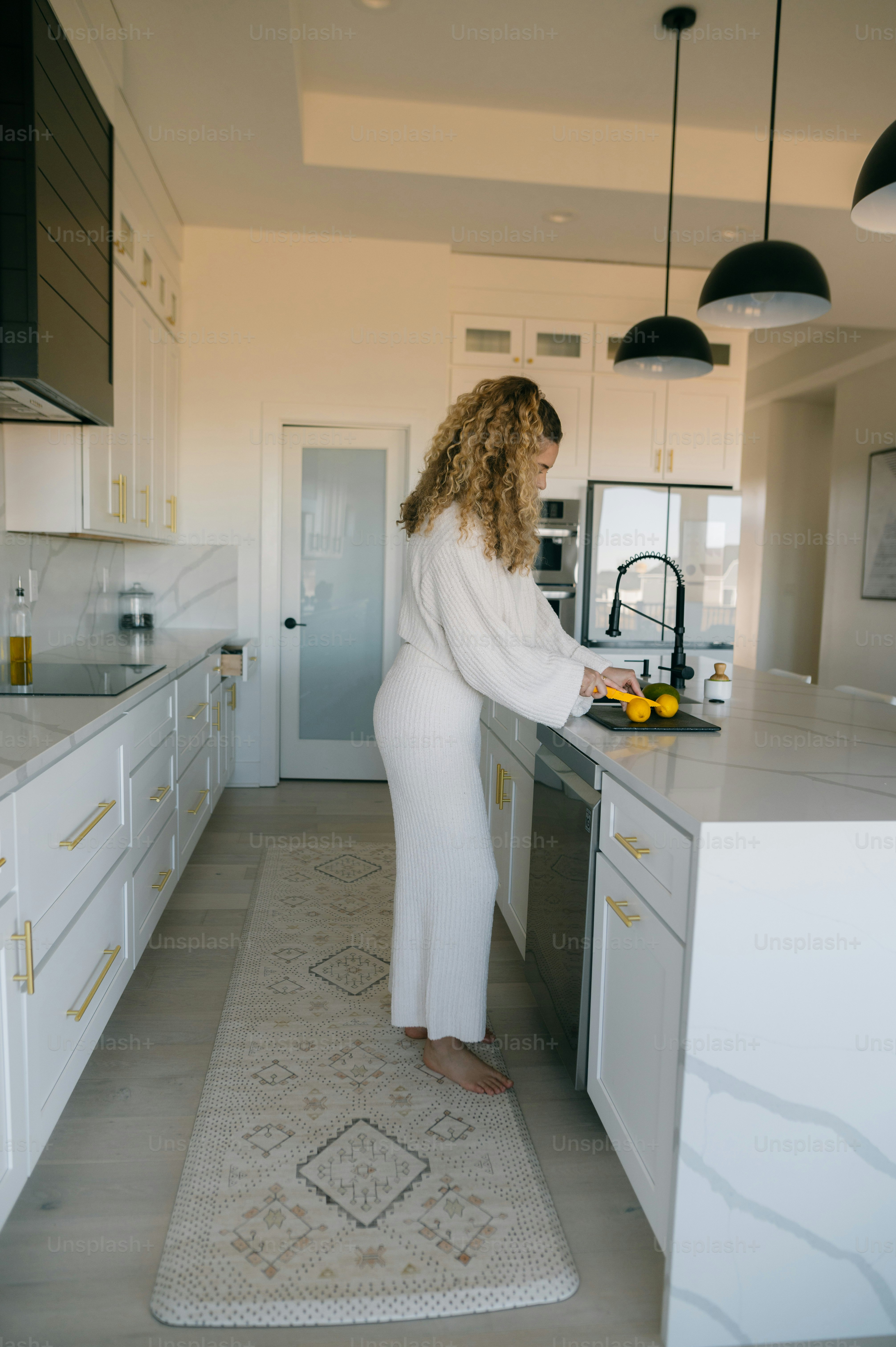 A woman standing in a kitchen preparing food photo – Woman Image on ...