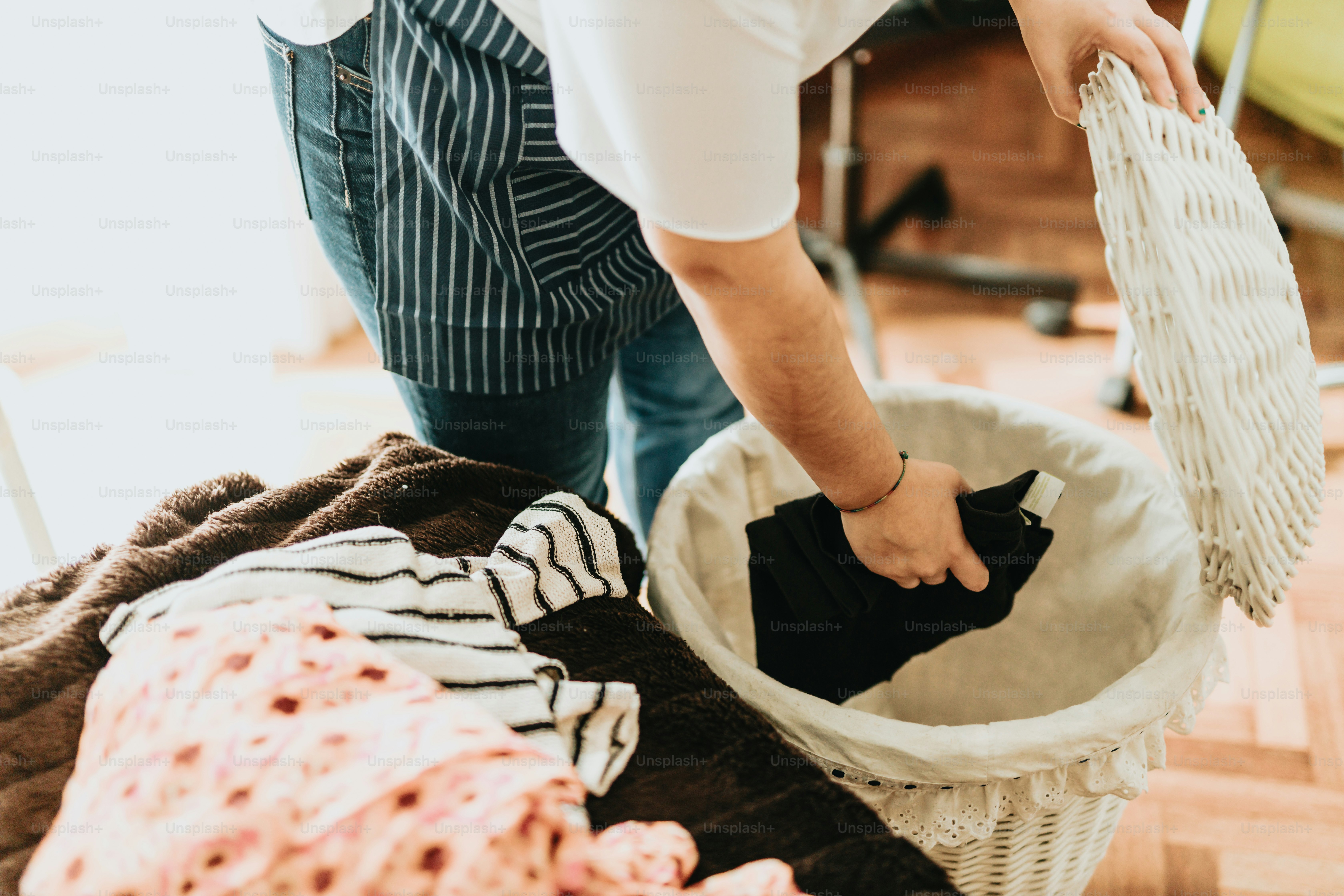 A person in an apron cleaning clothes in a basket photo – Cleaning ...