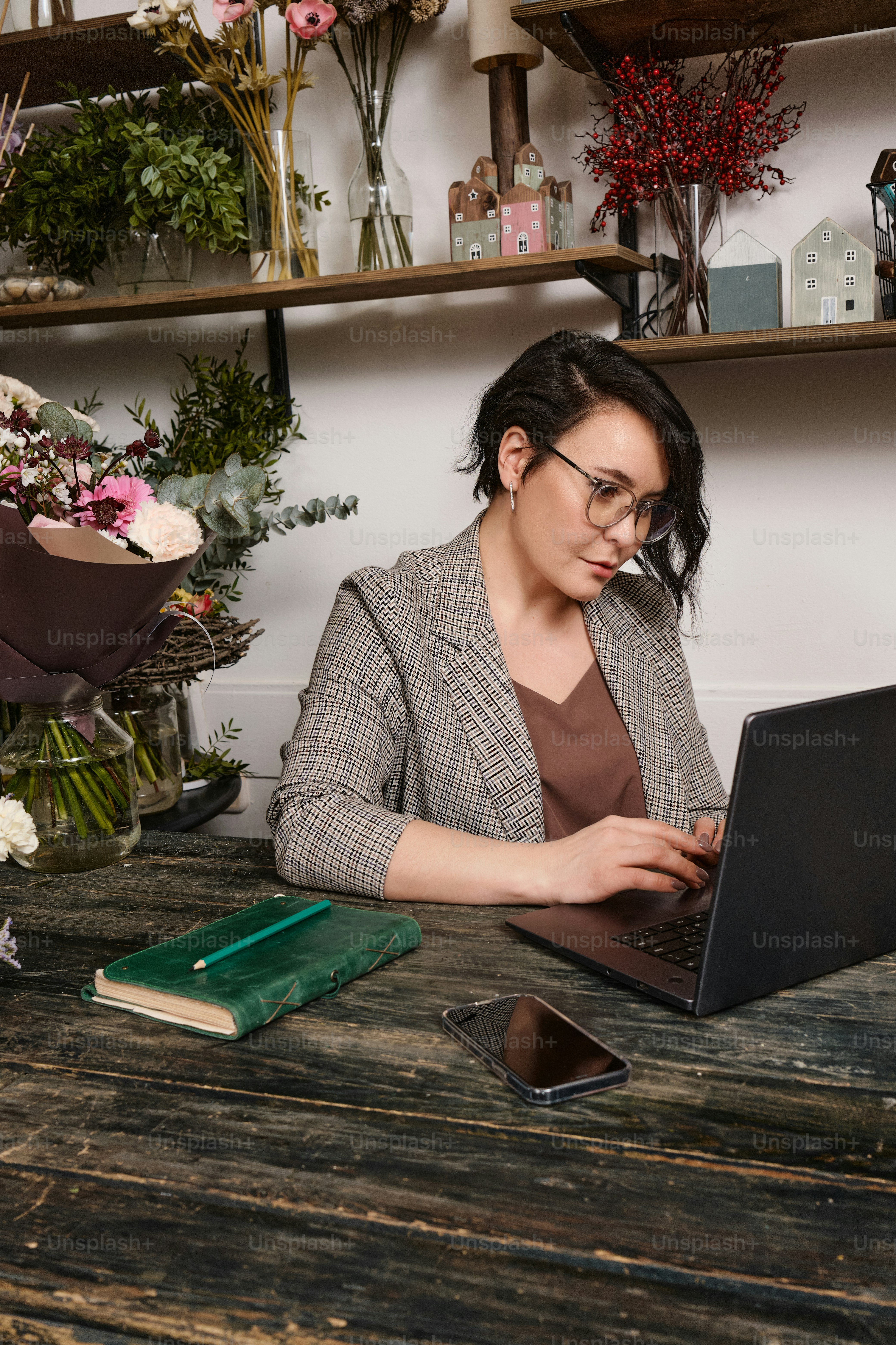 A woman sitting at a table using a laptop computer photo – Small ...