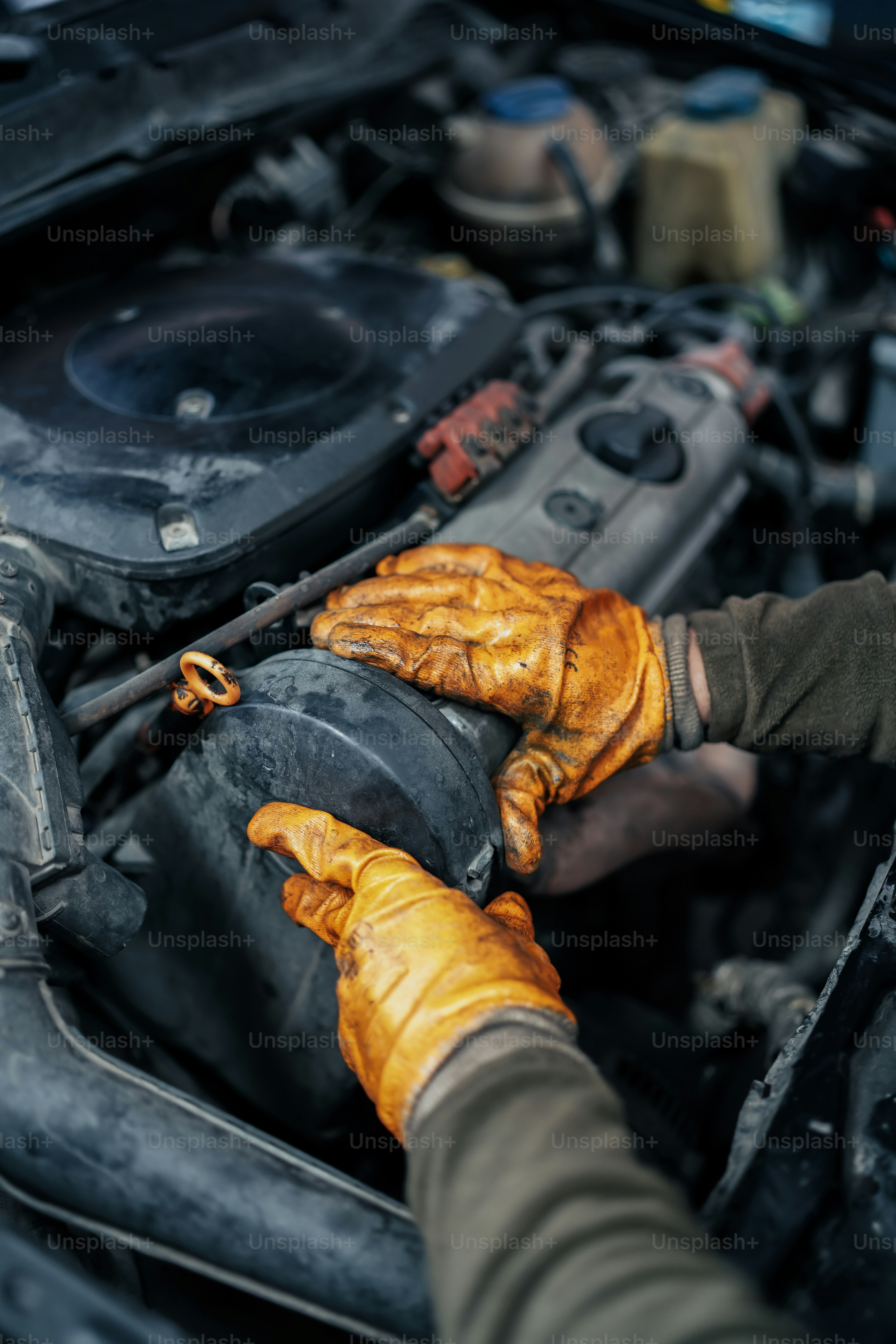 A man working on a car engine in a garage photo – Car oil Image on Unsplash