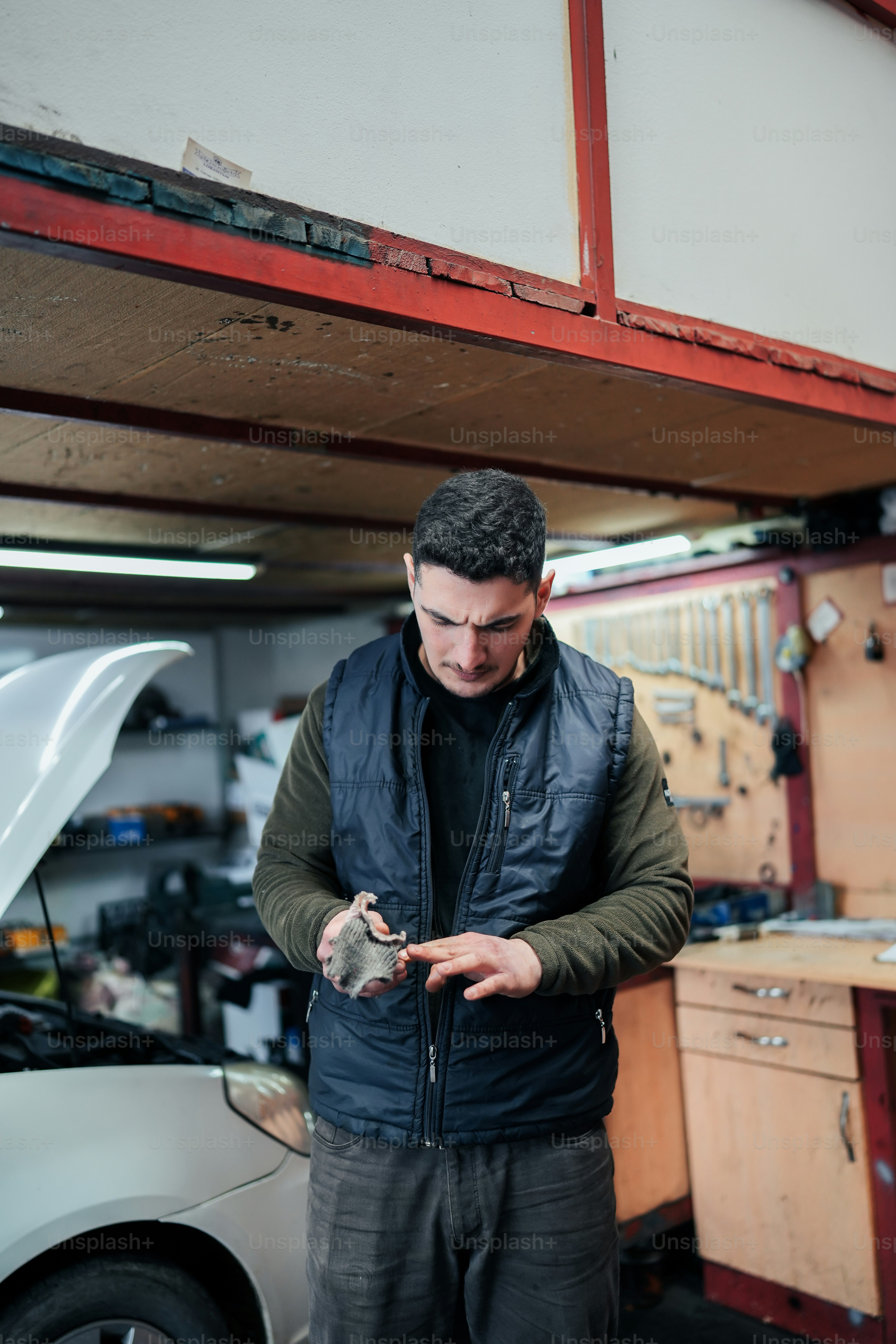 A man in a garage looking at a cell phone photo – Man Image on Unsplash