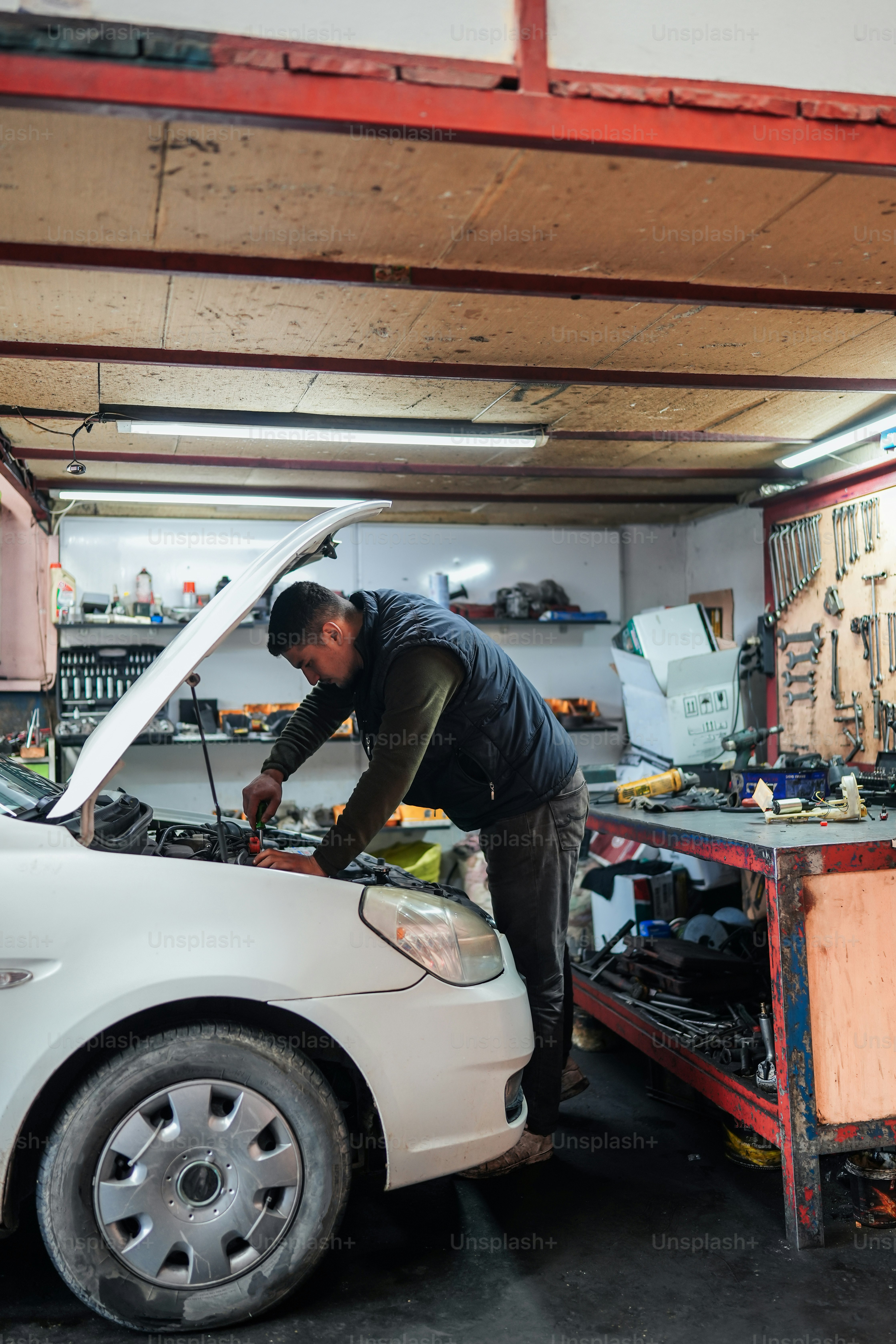 A man working on a car in a garage photo – Man Image on Unsplash