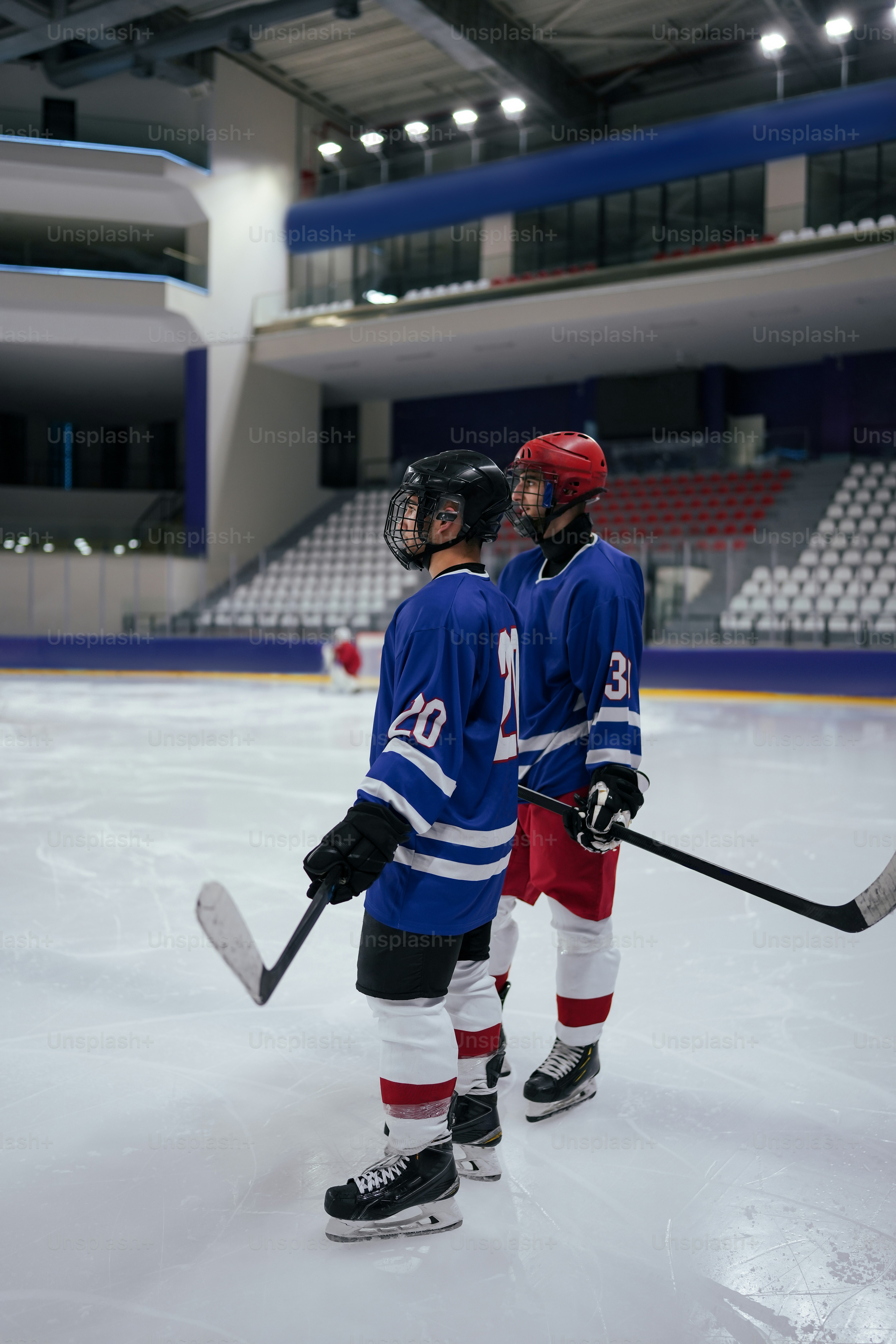 A couple of young men standing on top of a ice rink photo – Team Image ...
