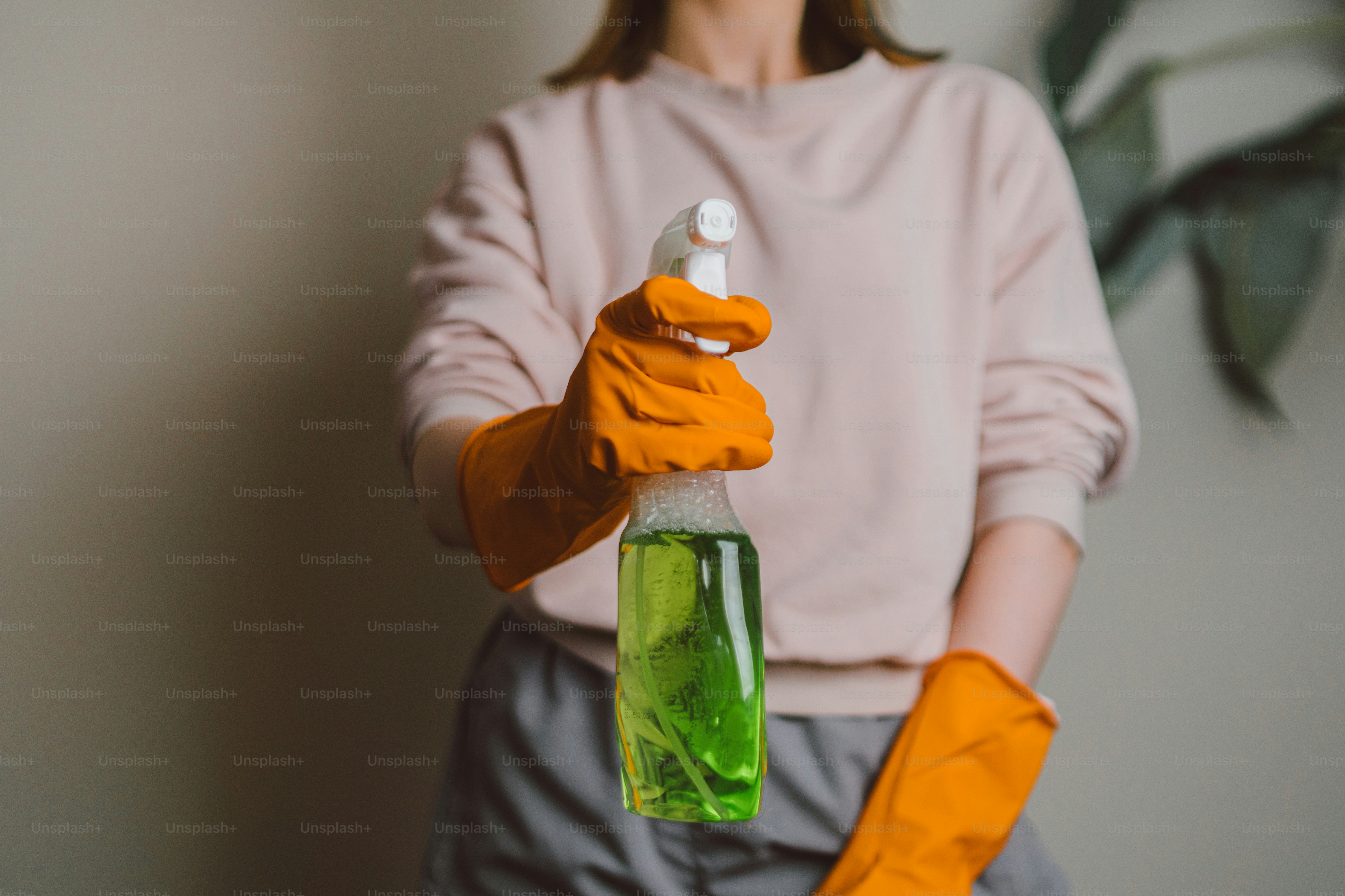 A person wearing orange gloves holding a bottle of cleaner photo ...
