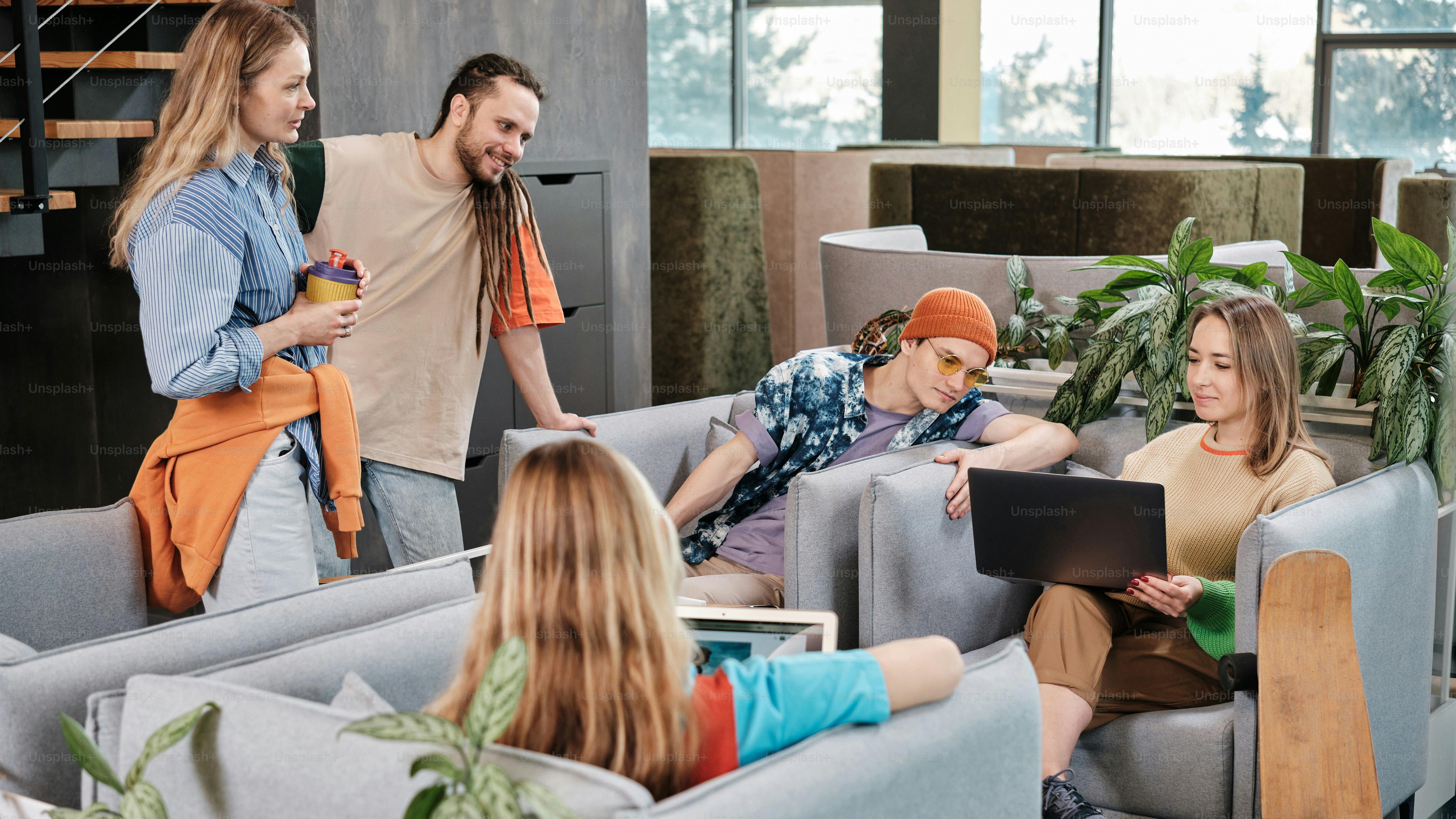 A group of people standing and sitting around a laptop photo – Meeting ...