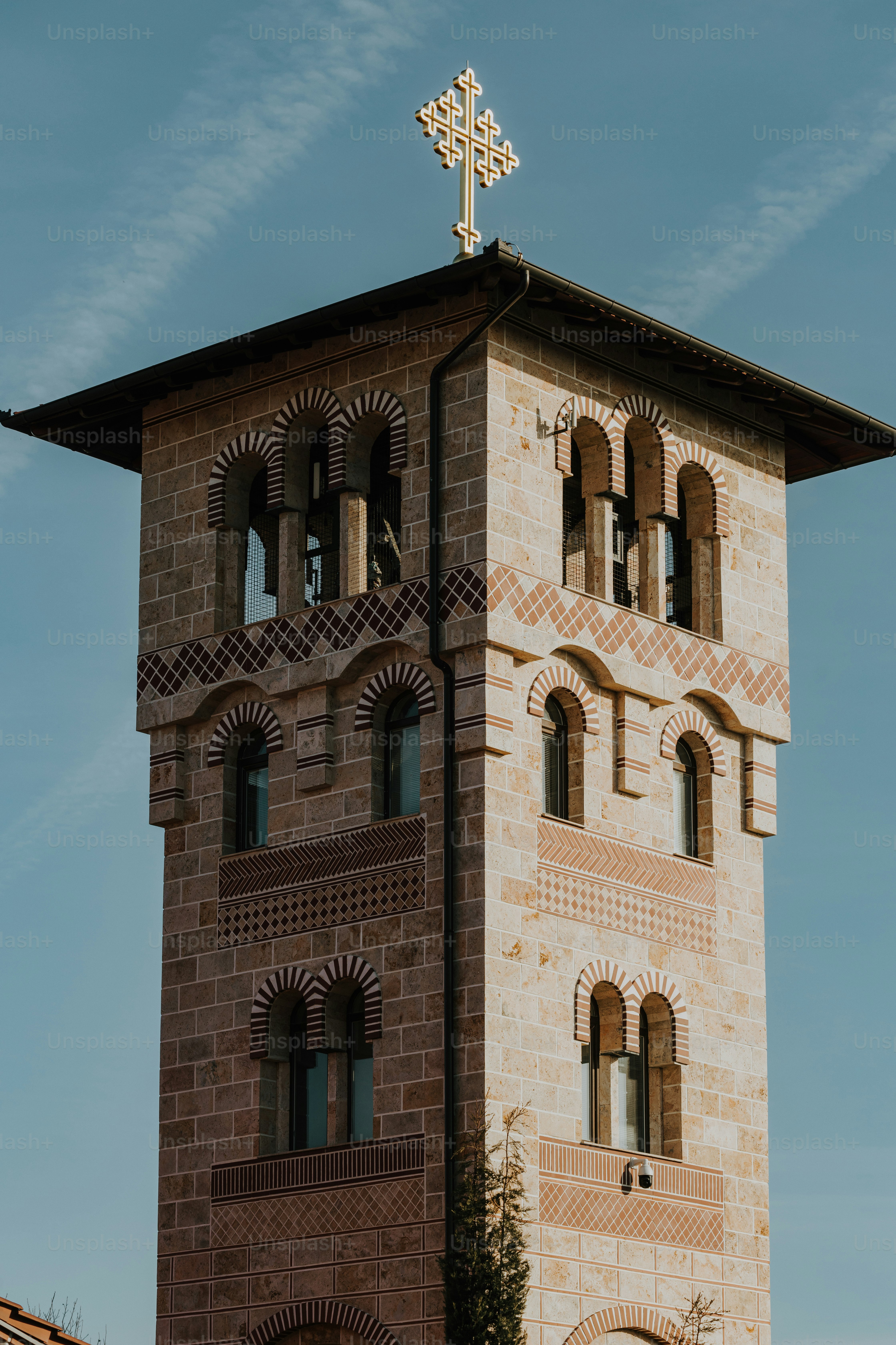 A tall brick building with a cross on top of it photo – Building Image ...