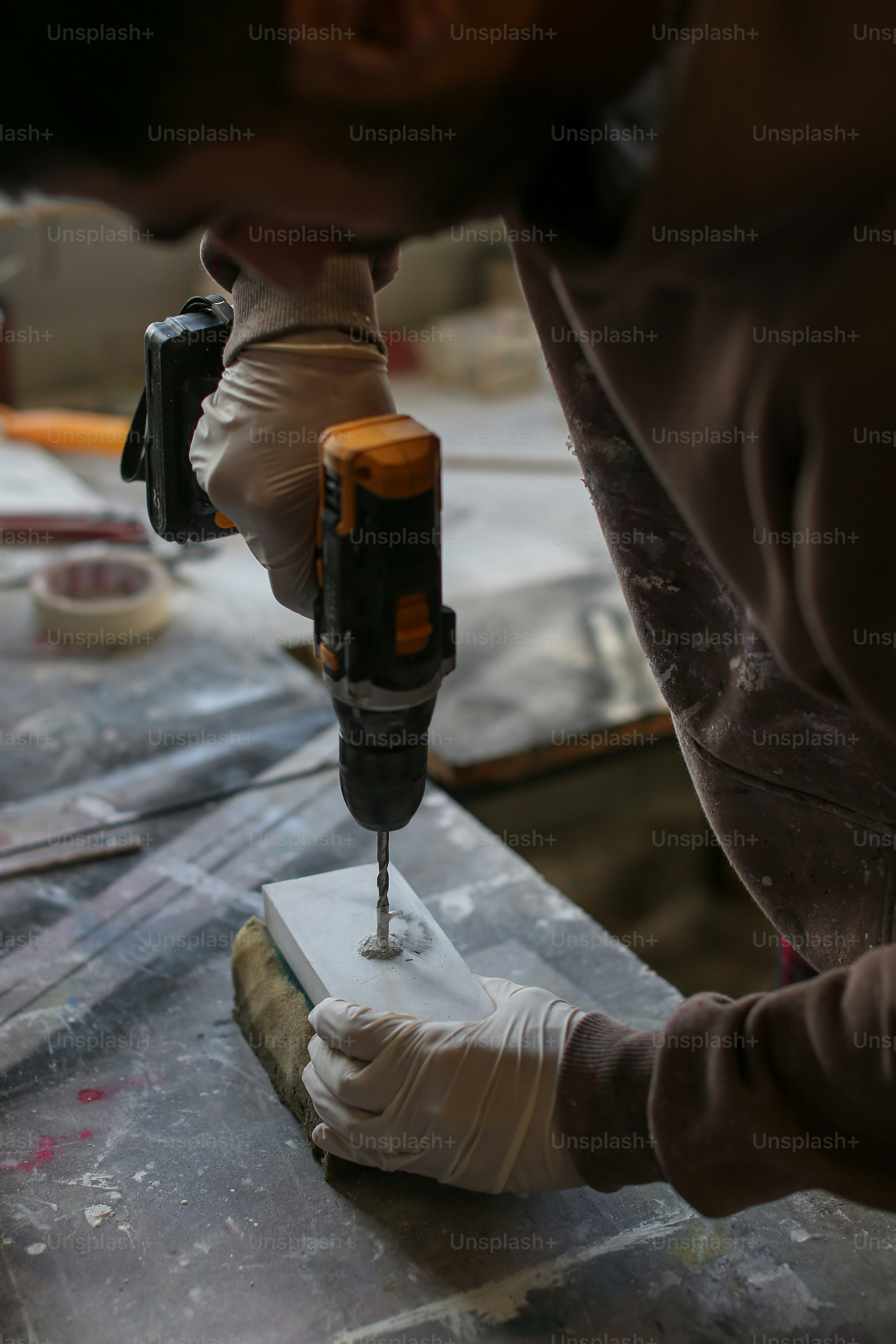 A man uses a drill to drill a piece of paper photo – Sculpture Image on ...