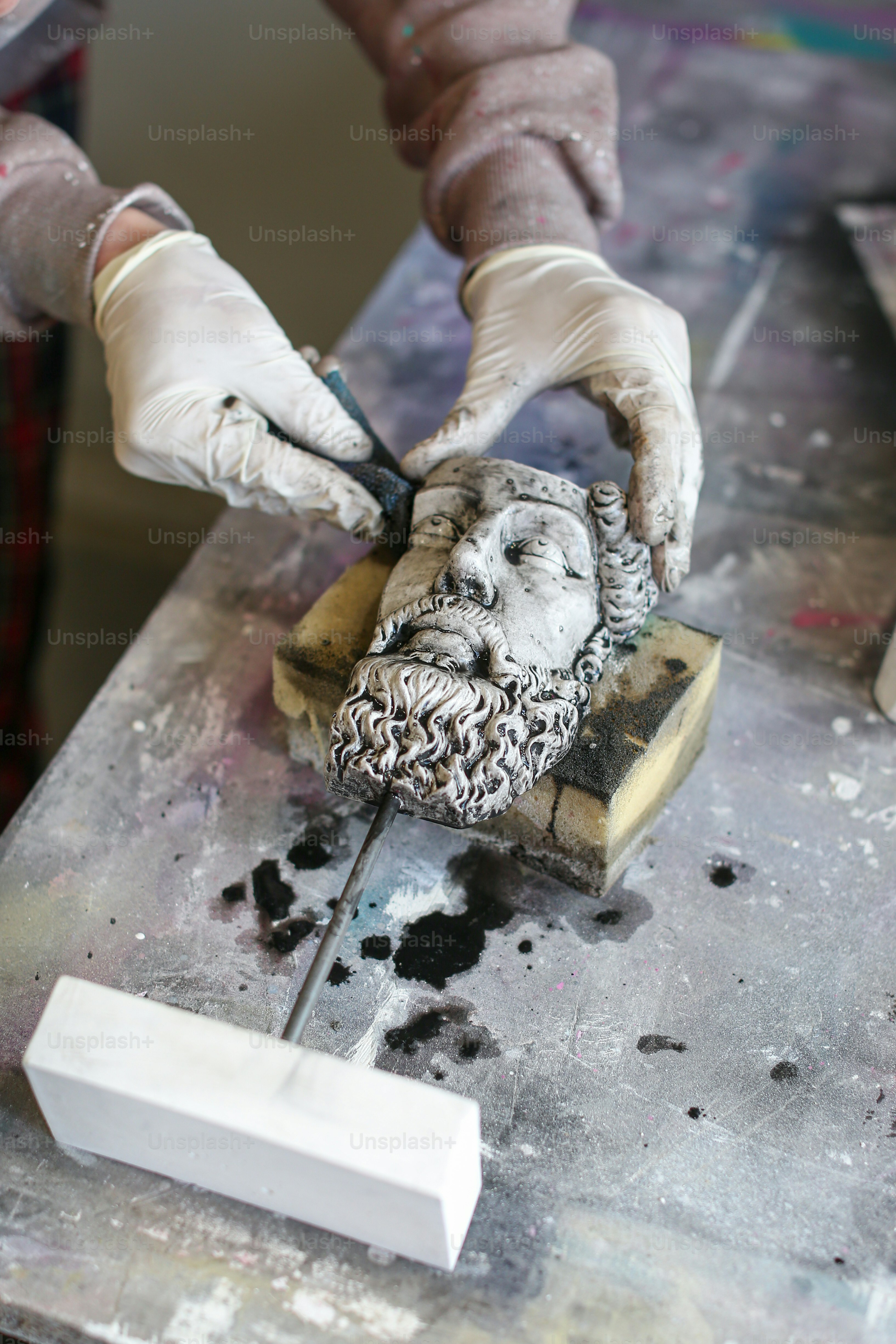 A person is carving a statue of a man's head photo – Artist Image on ...