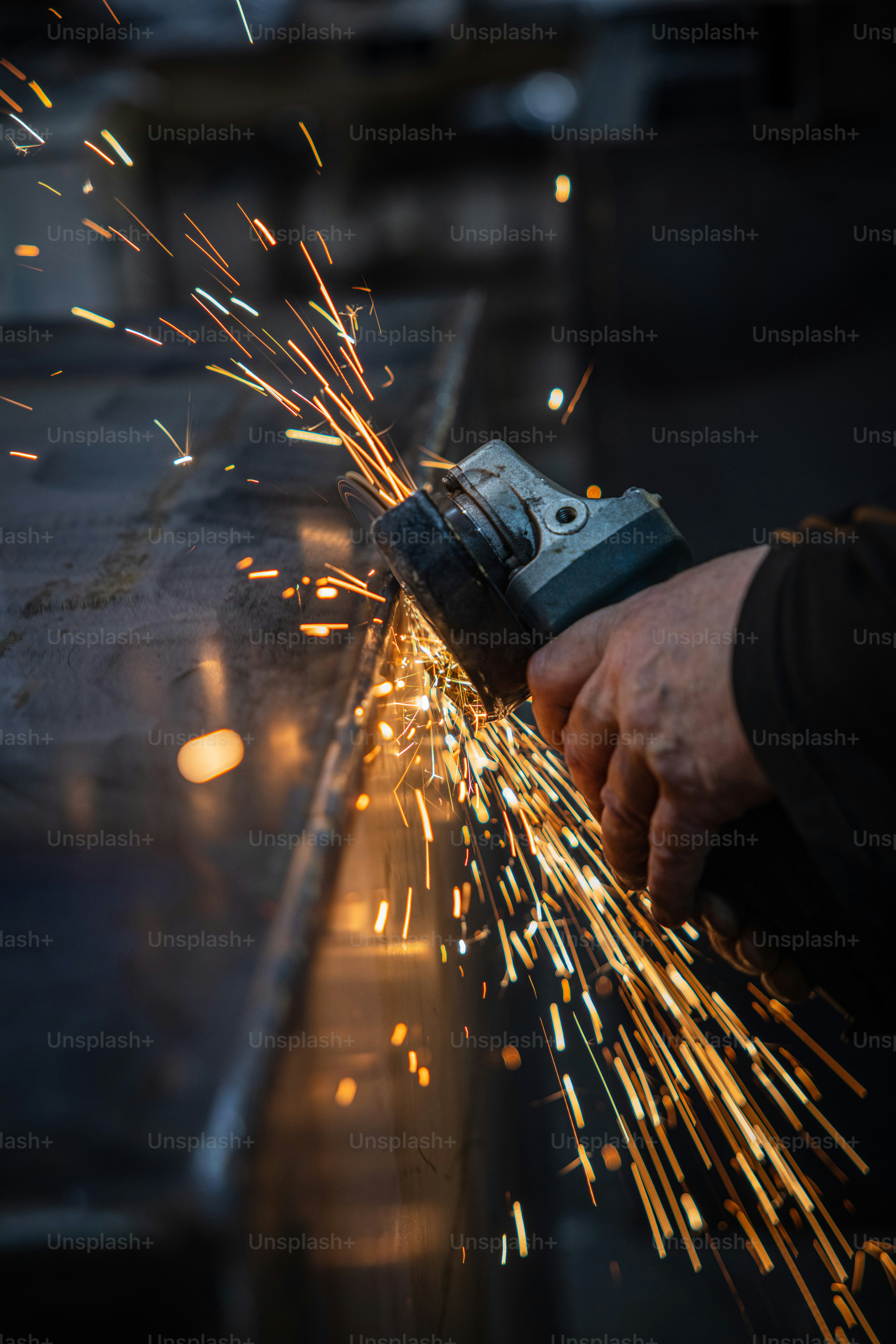 A person using a grinder on a piece of metal photo – Manufacturing ...