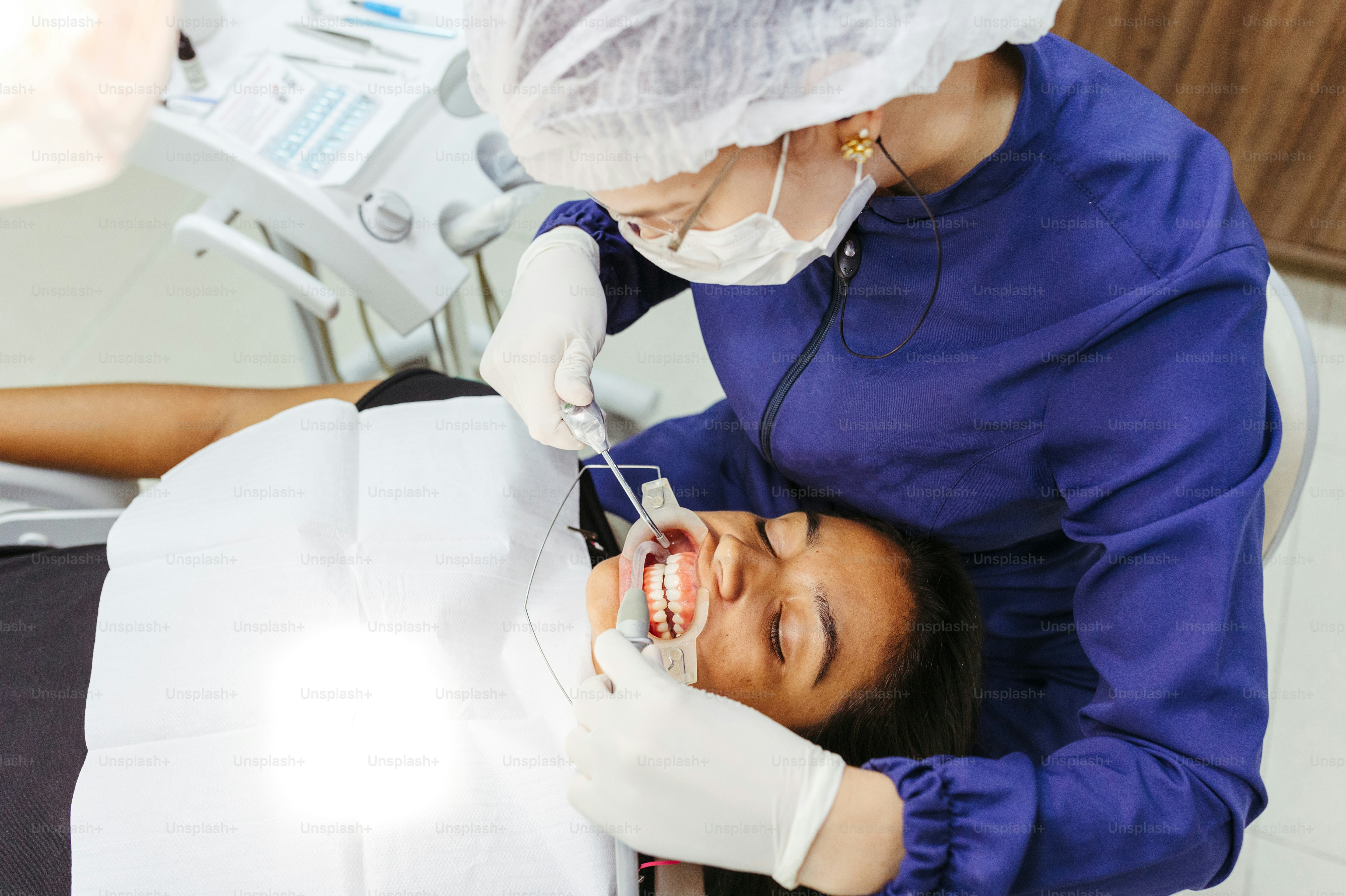 A woman getting her teeth checked by a dentist photo – Patients Image ...