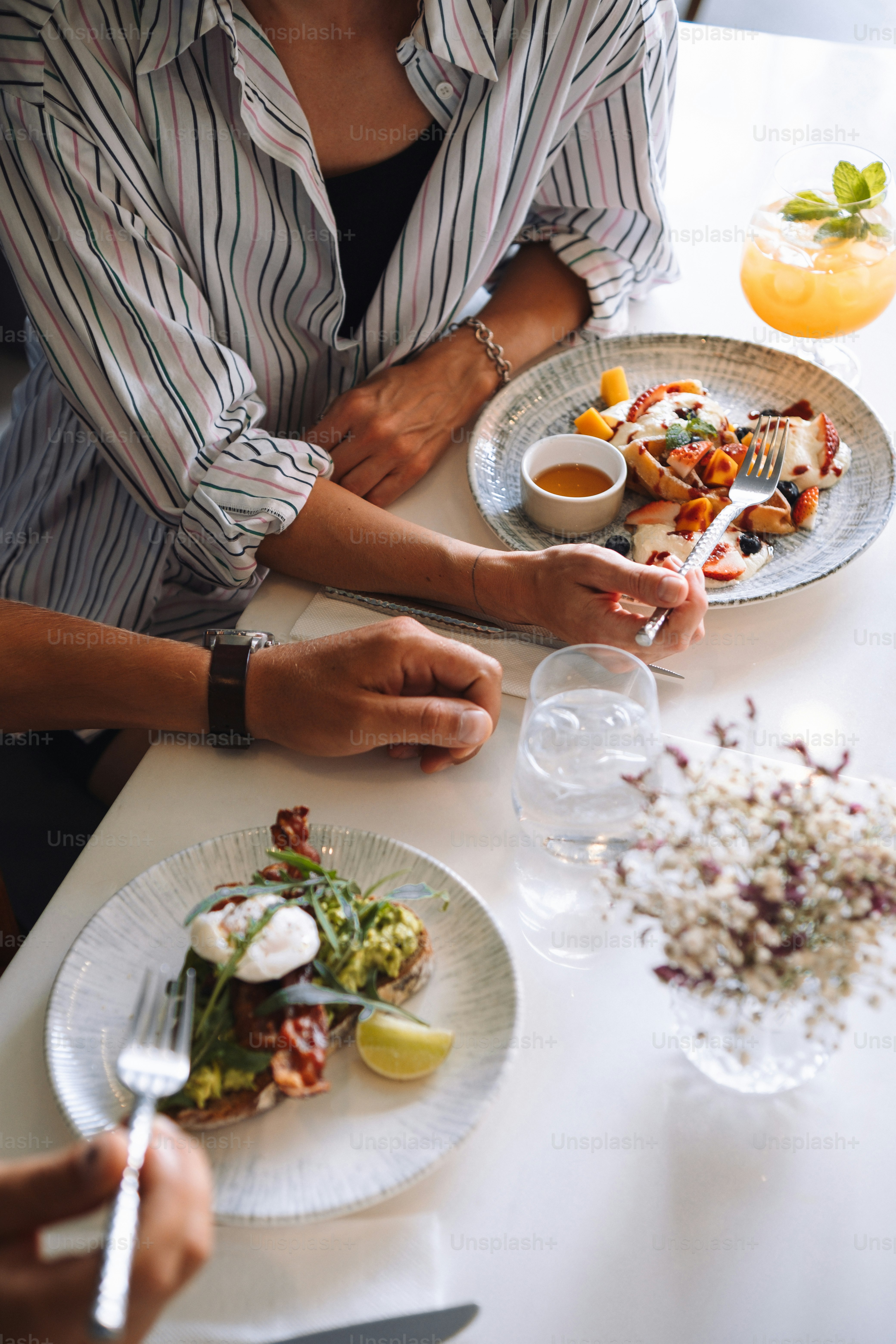 Un couple de personnes assises à une table avec des assiettes de ...