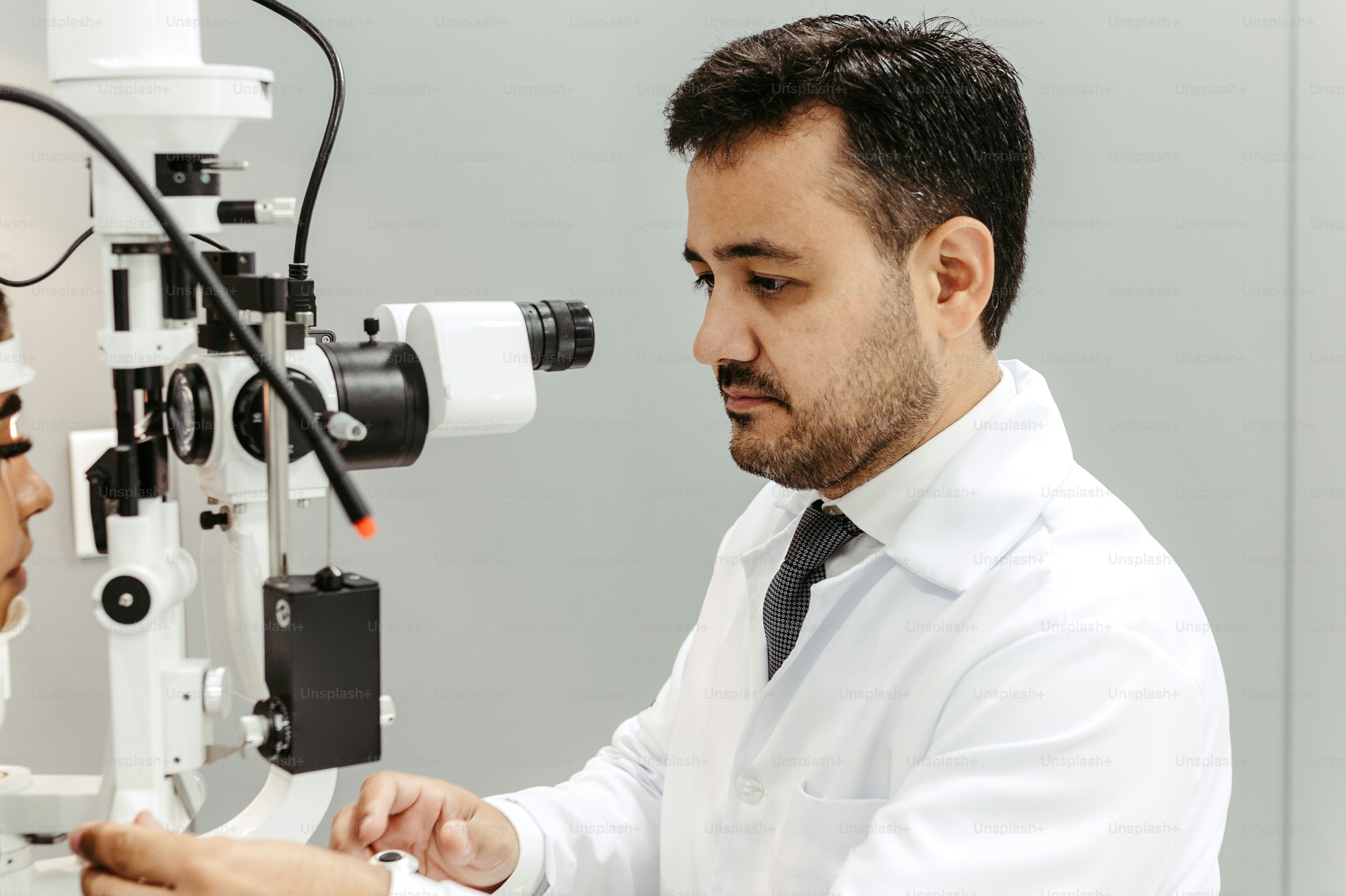 A man and a woman looking through a microscope photo – Optometrist ...
