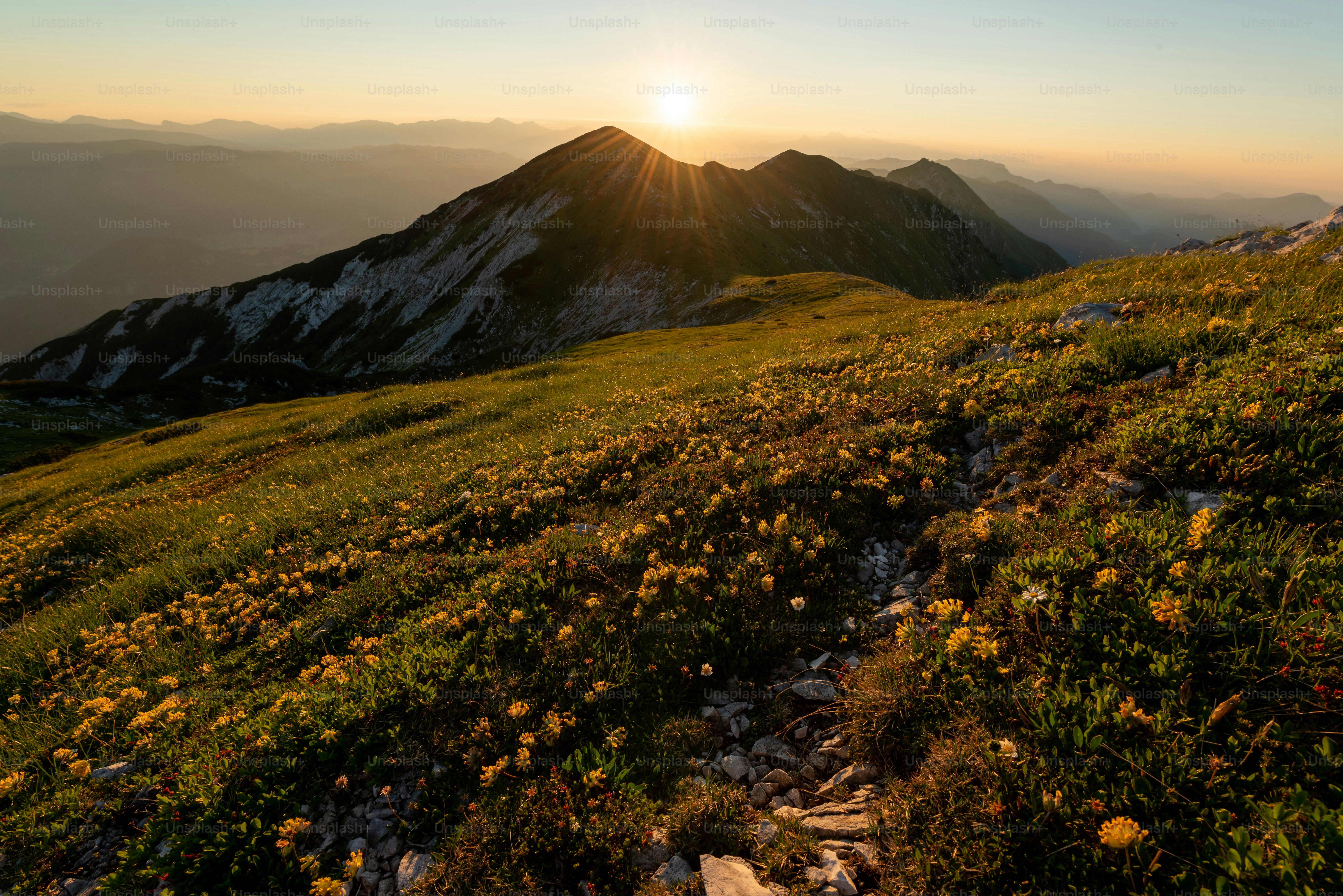 The sun is setting over a grassy hill photo – Mountains Image on Unsplash