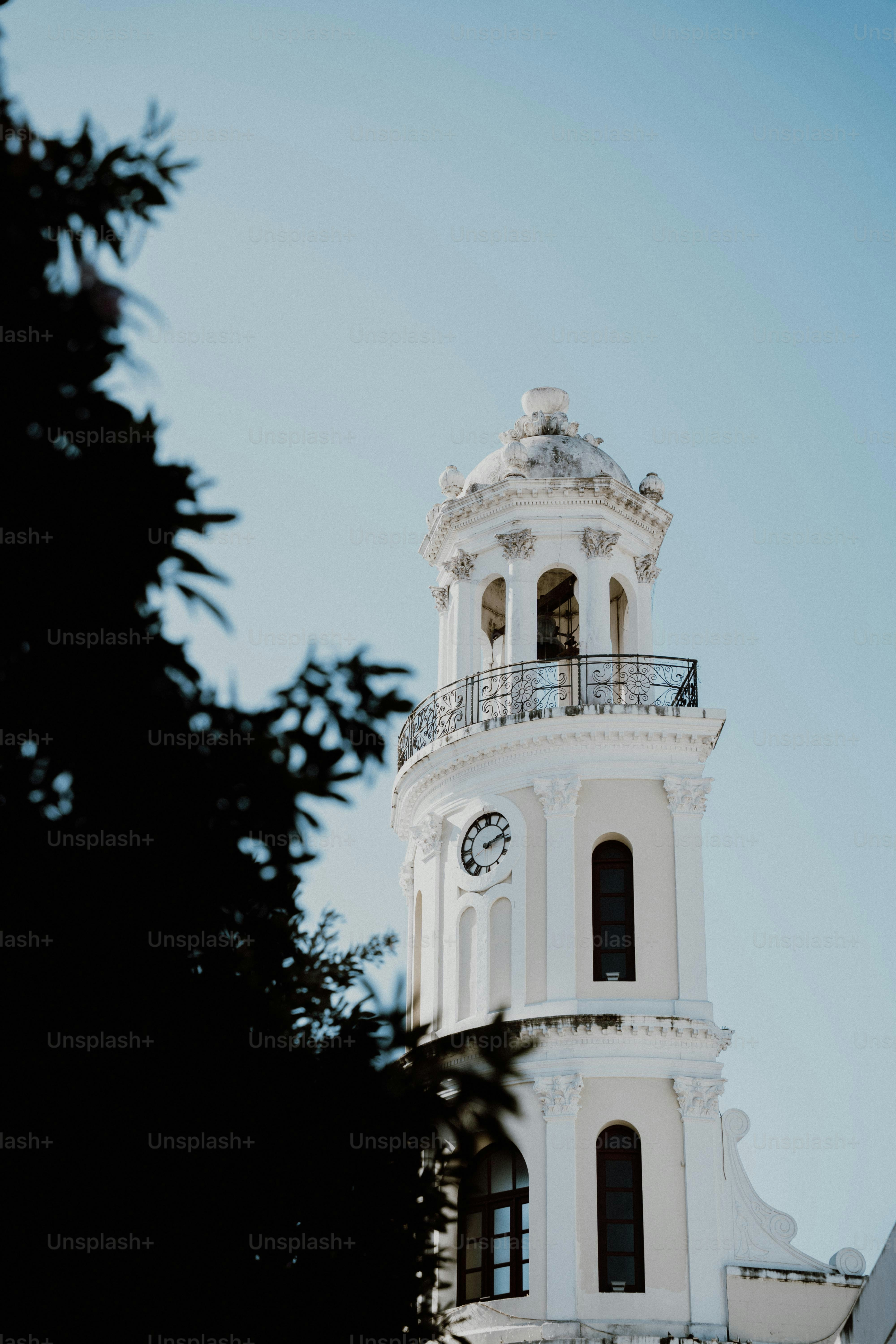 A tall white clock tower with a clock on each of it's sides photo ...