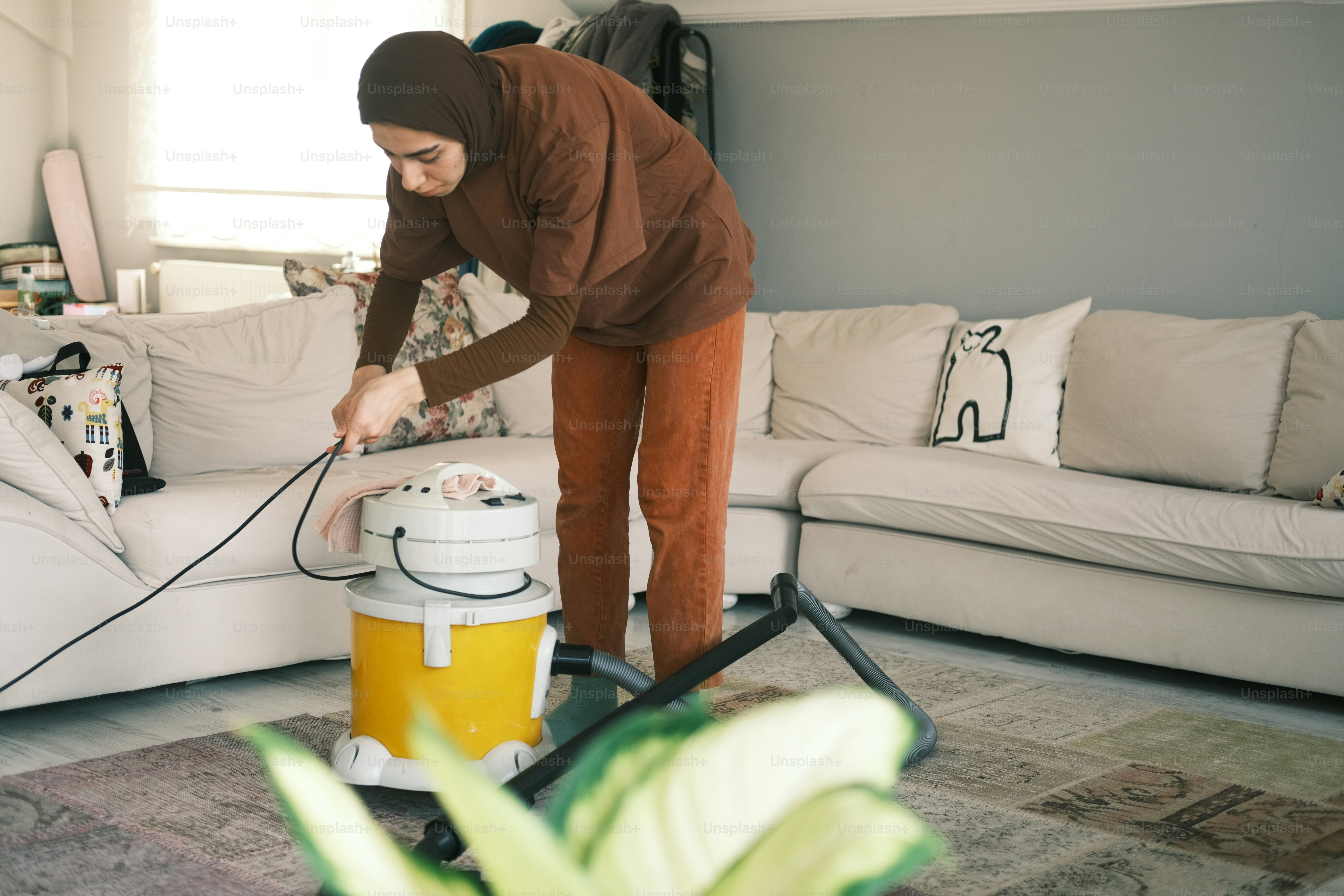 A woman using a vacuum to clean a living room photo – Tidy up Image on ...