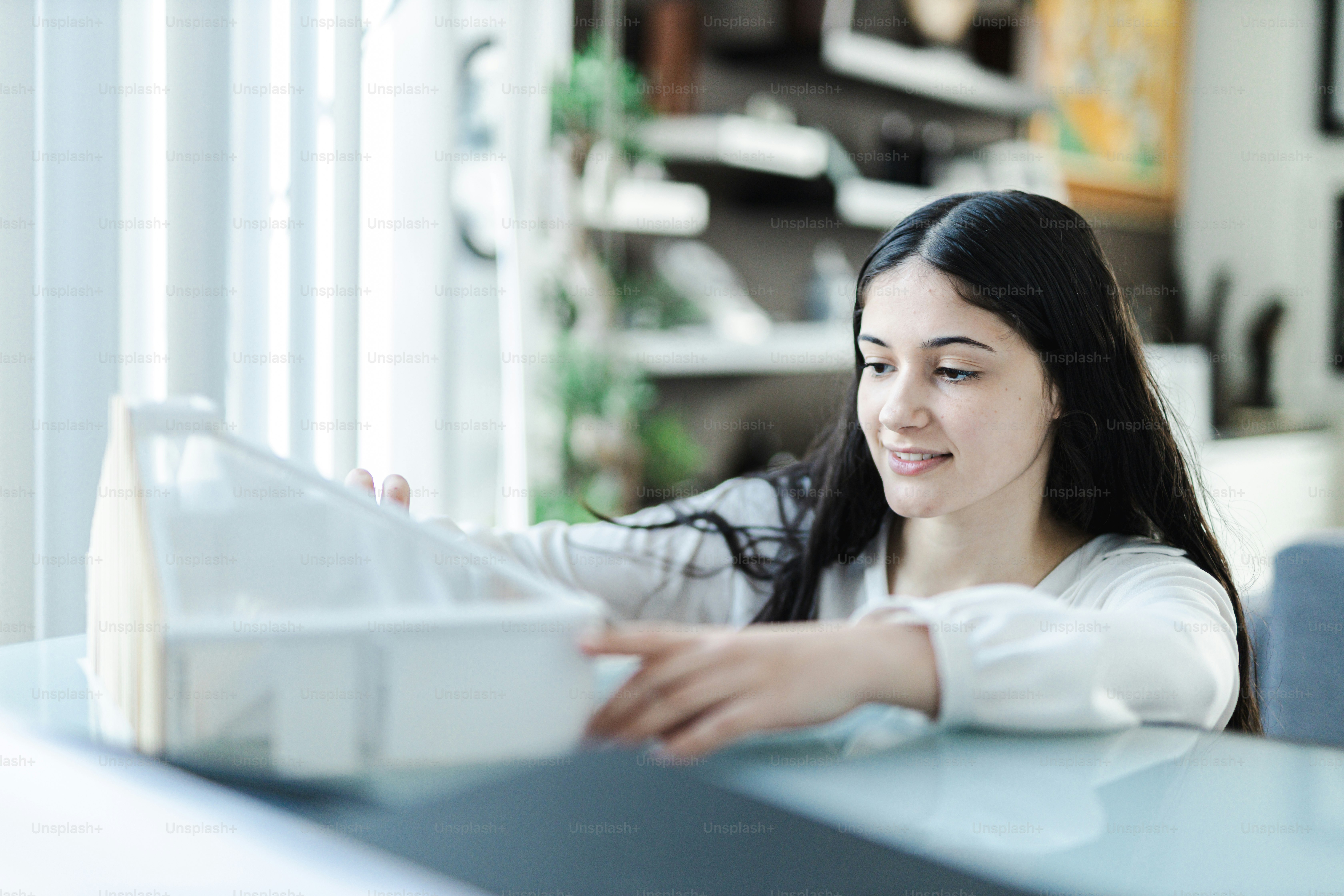 A woman sitting at a table looking at a box photo – Job Image on Unsplash