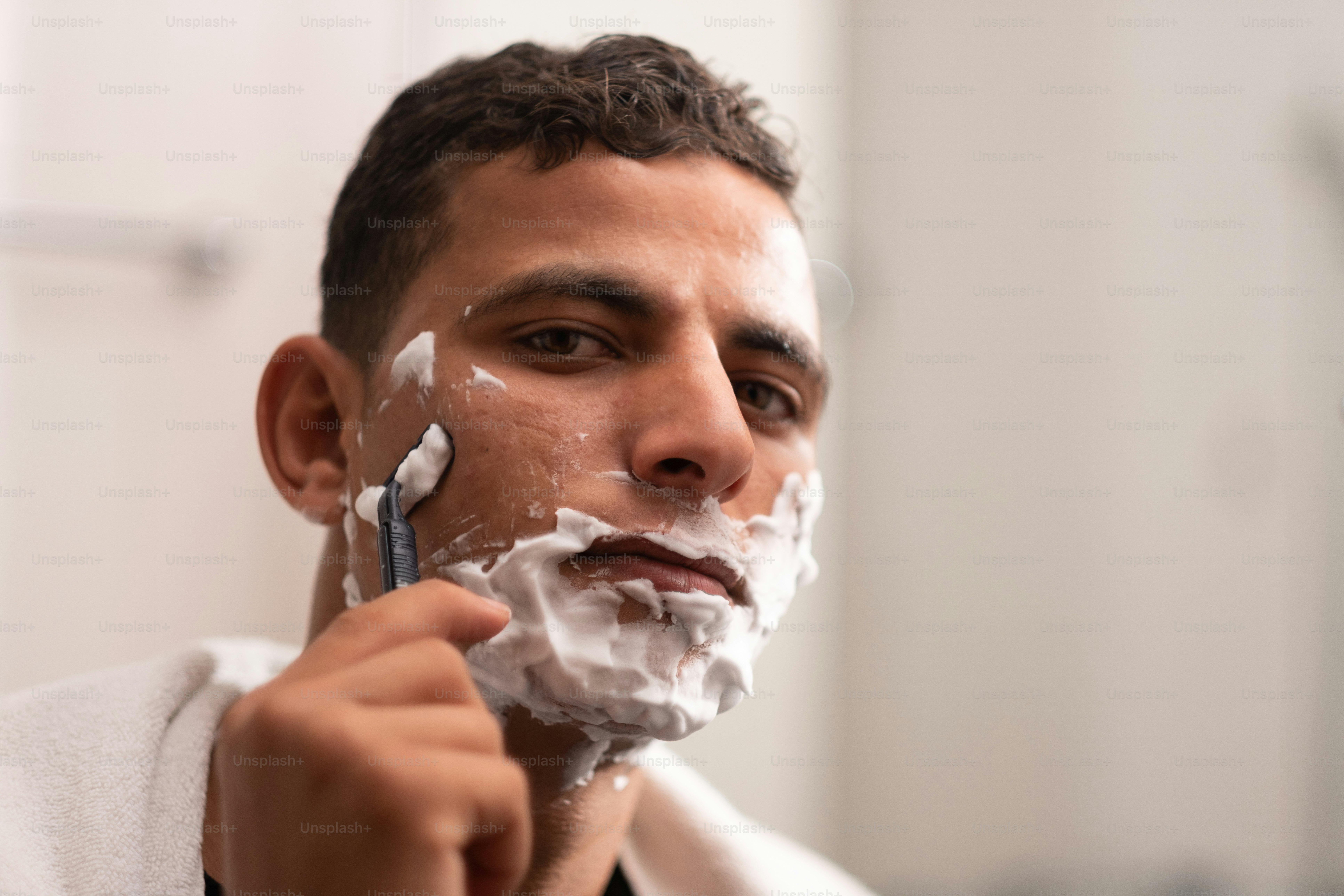 A man shaving his face with a razor photo – Razor Image on Unsplash