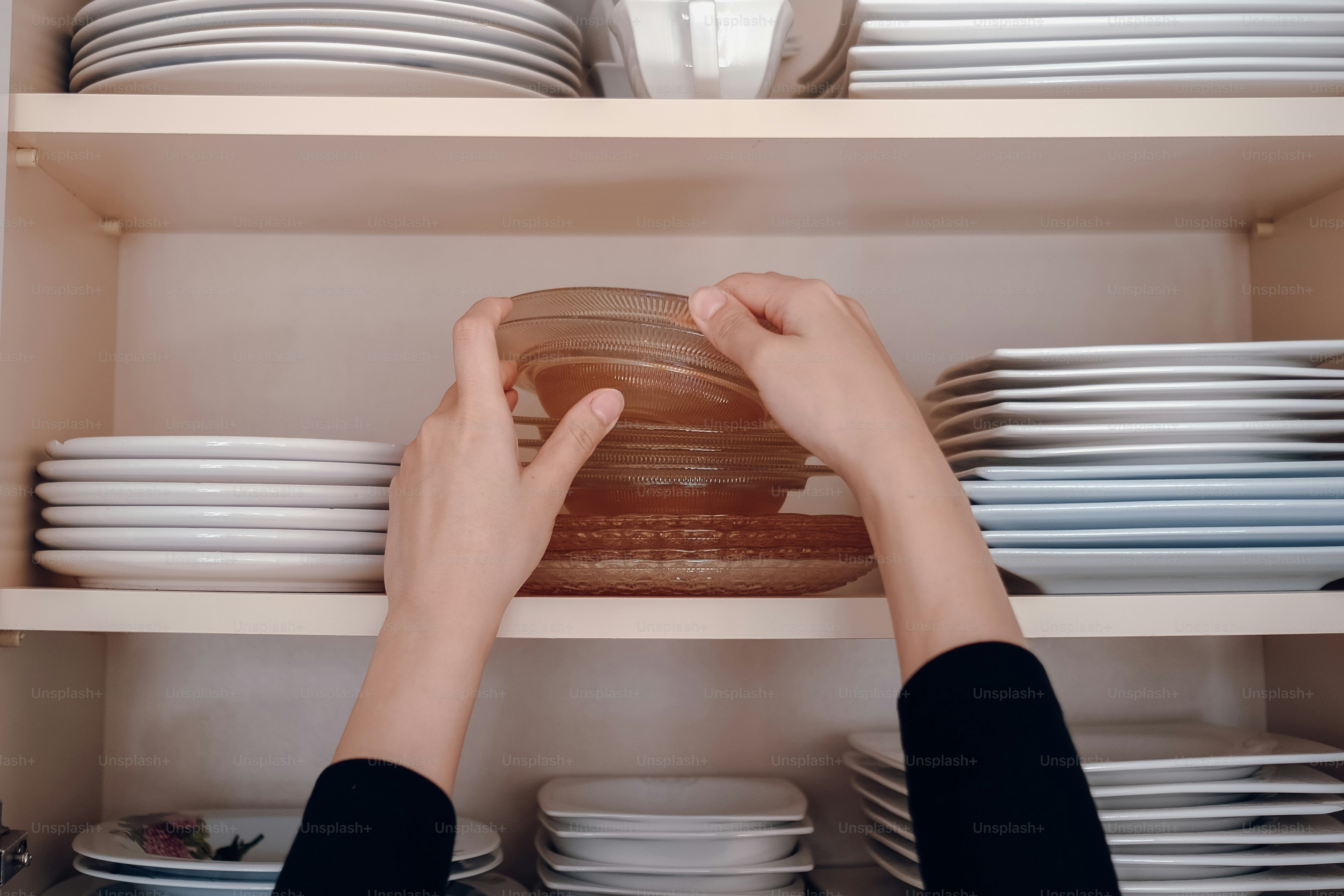 A person reaching for a plate on a shelf photo – Kitchen cupboard Image ...