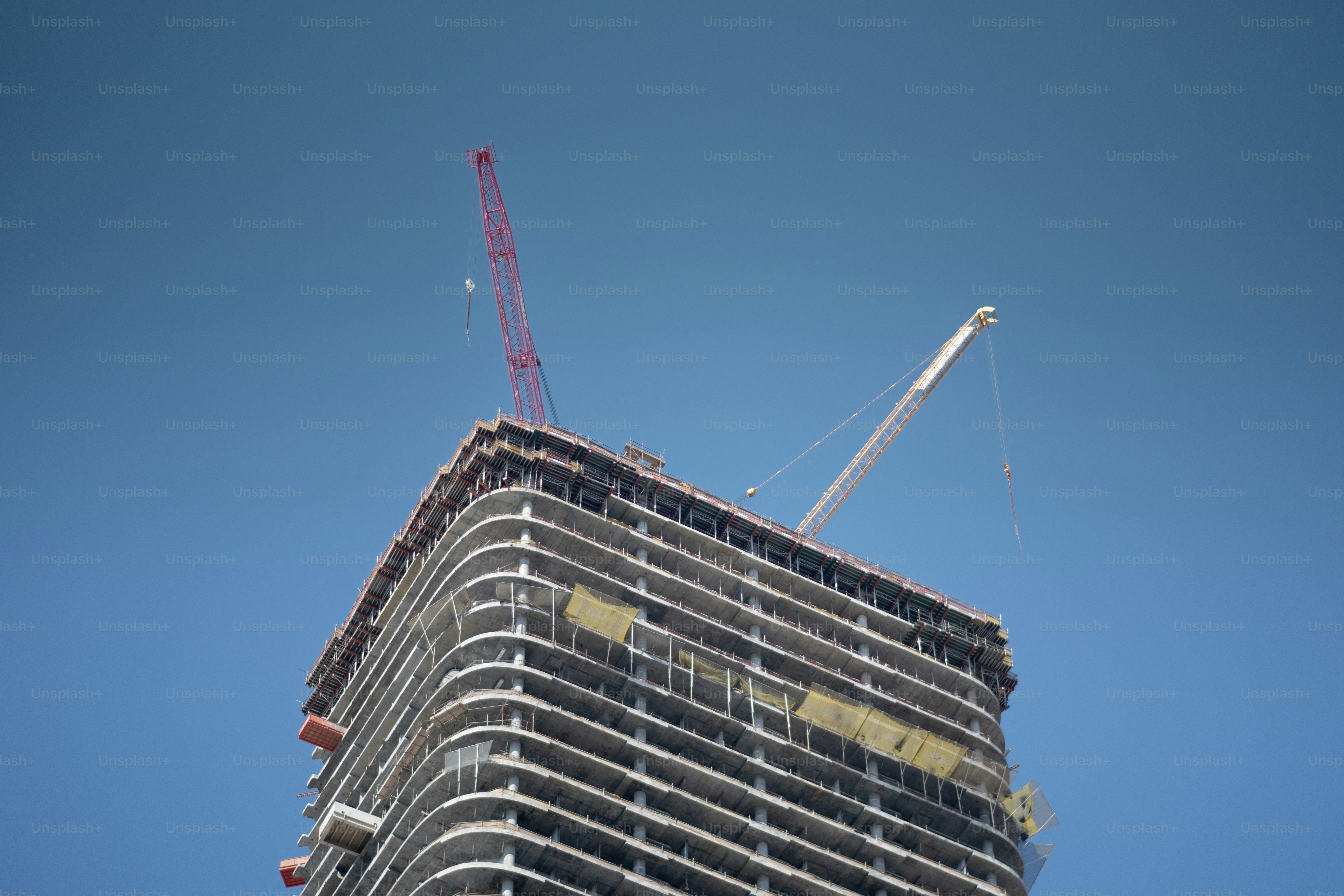 A tall building with a crane on top of it photo – Construction Image on ...