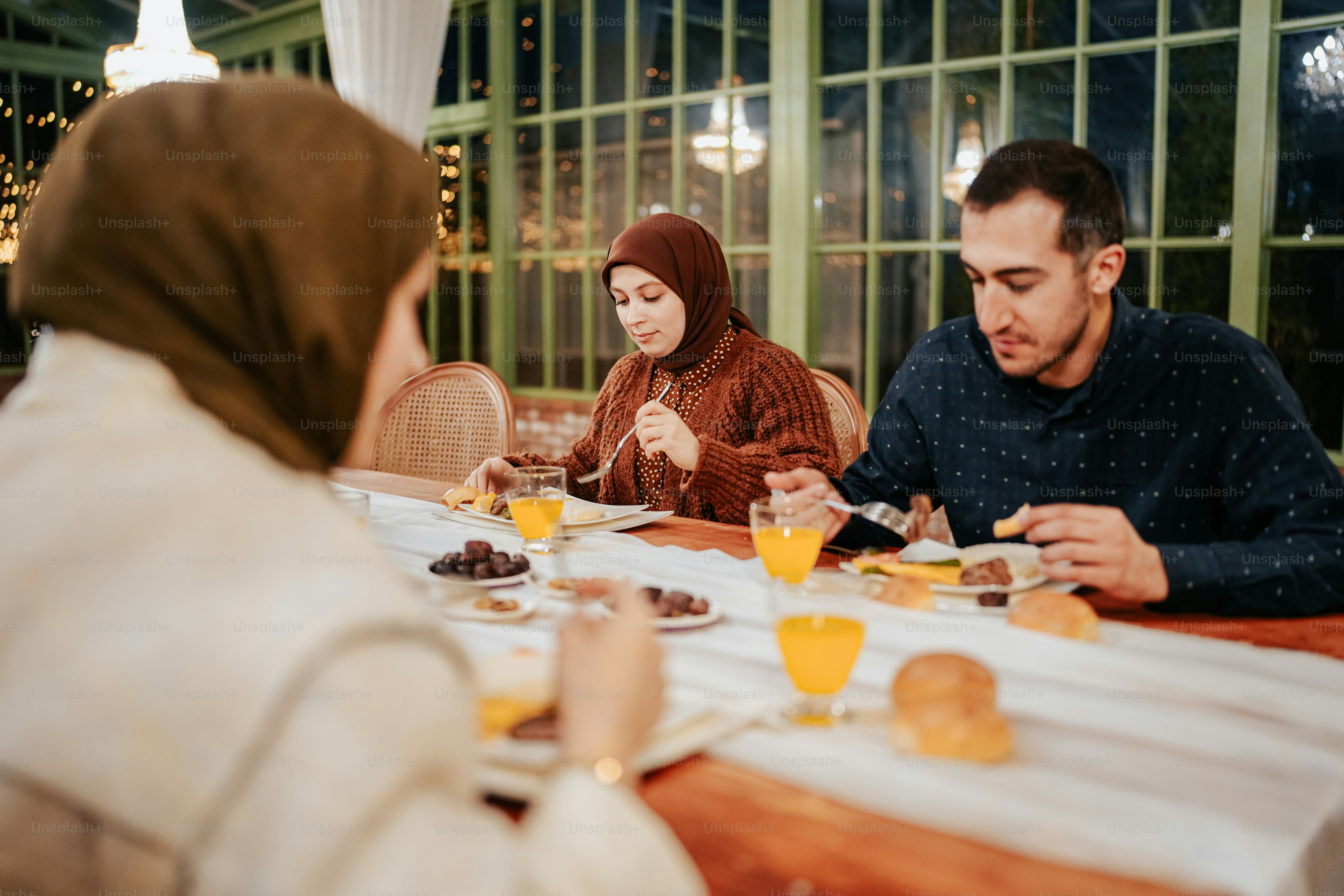 A group of people sitting around a table eating food photo – Meal Image ...