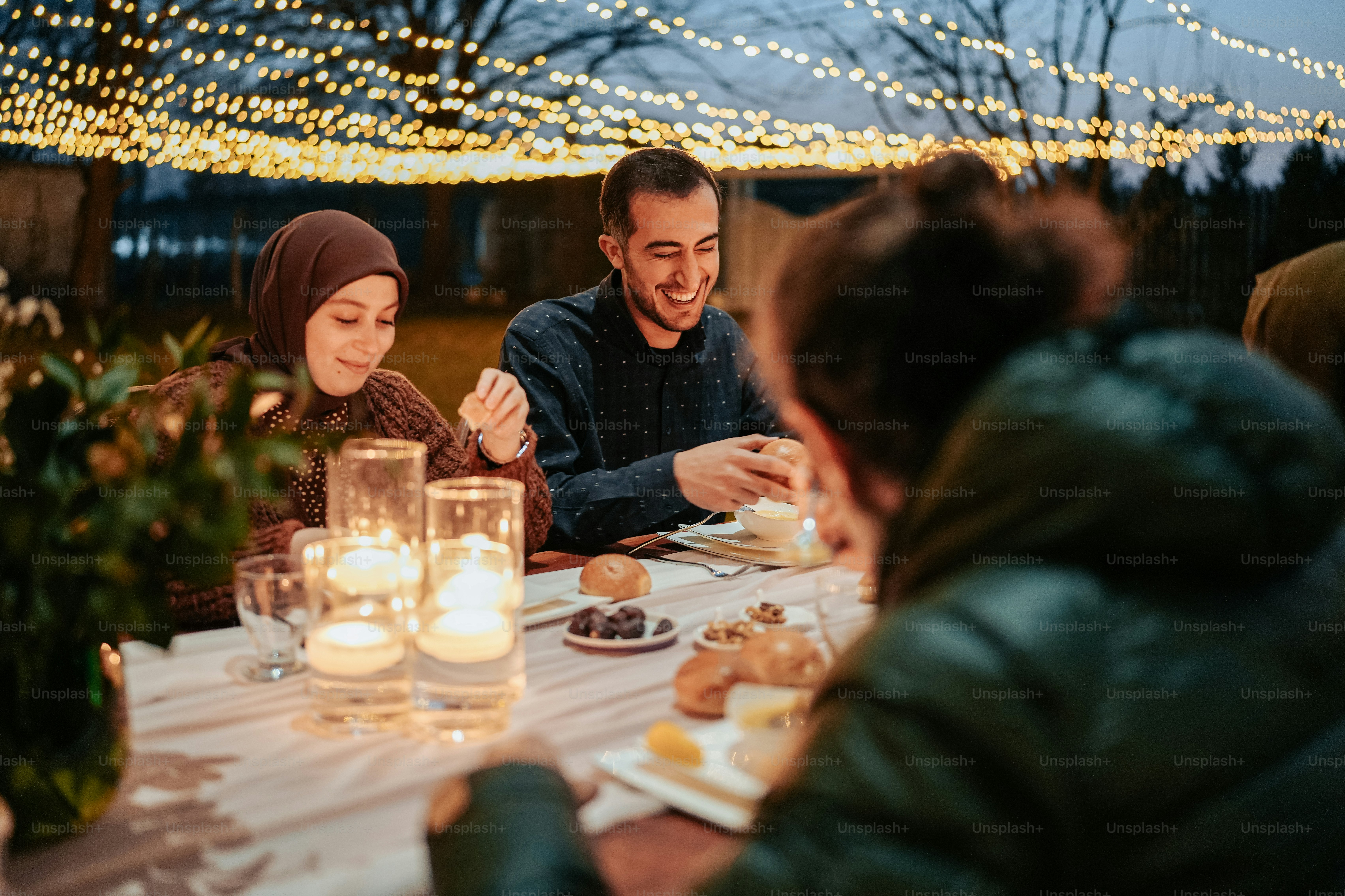 A group of people sitting around a table eating food photo – Outdoor ...
