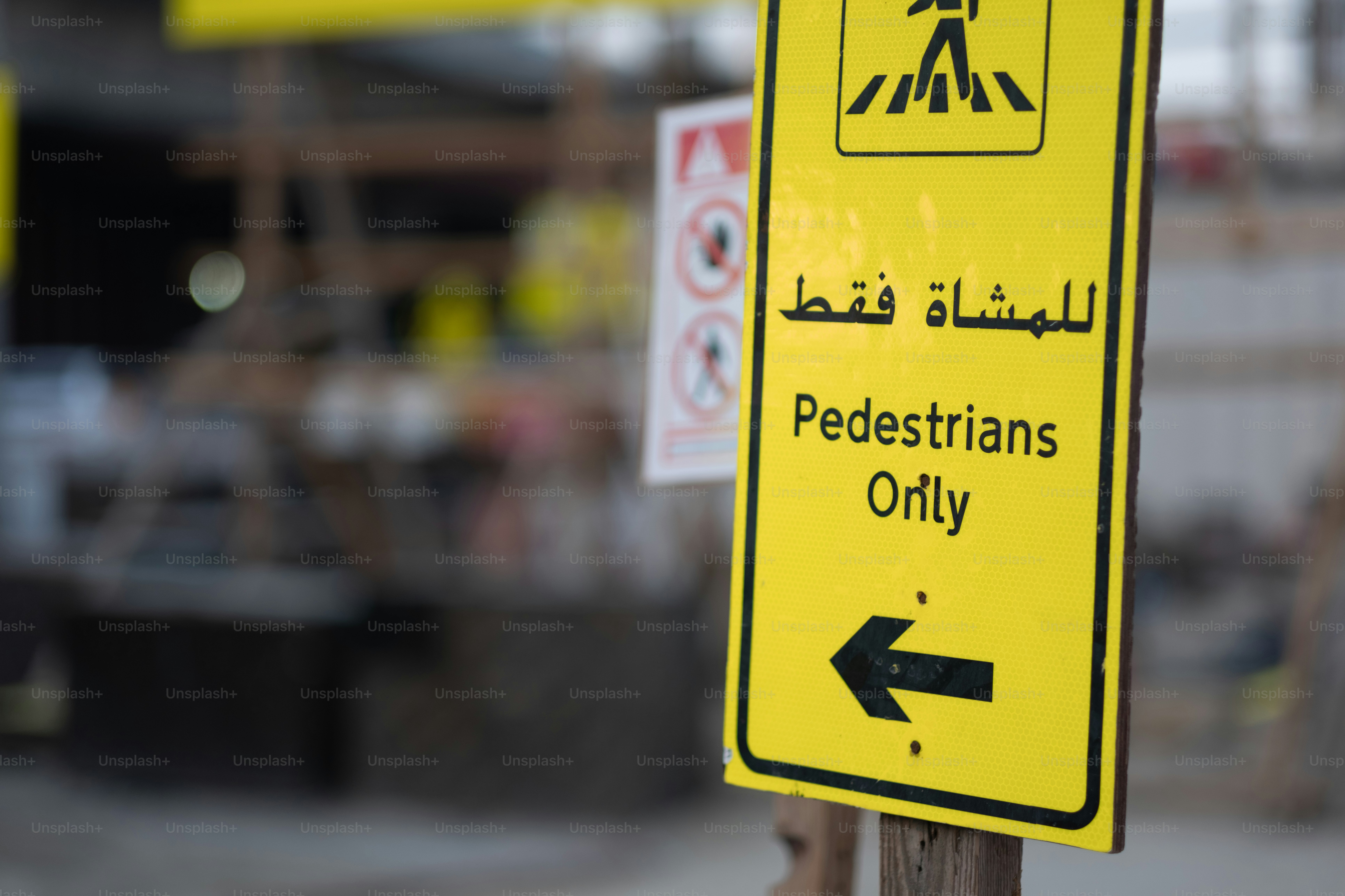 A yellow and black safety first sign on a pole photo – Construction ...