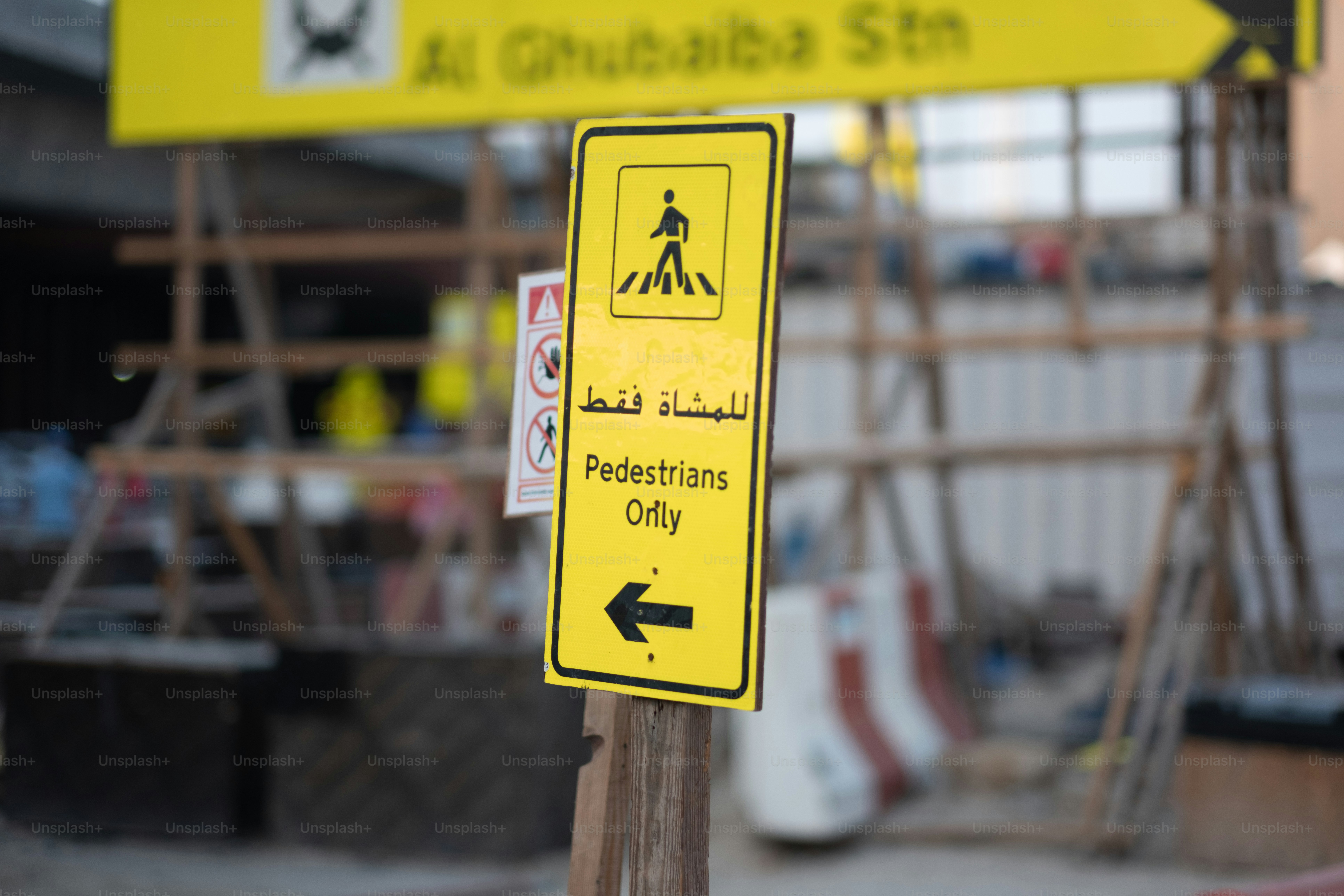 A yellow and black safety first sign on a pole photo – Building Image ...