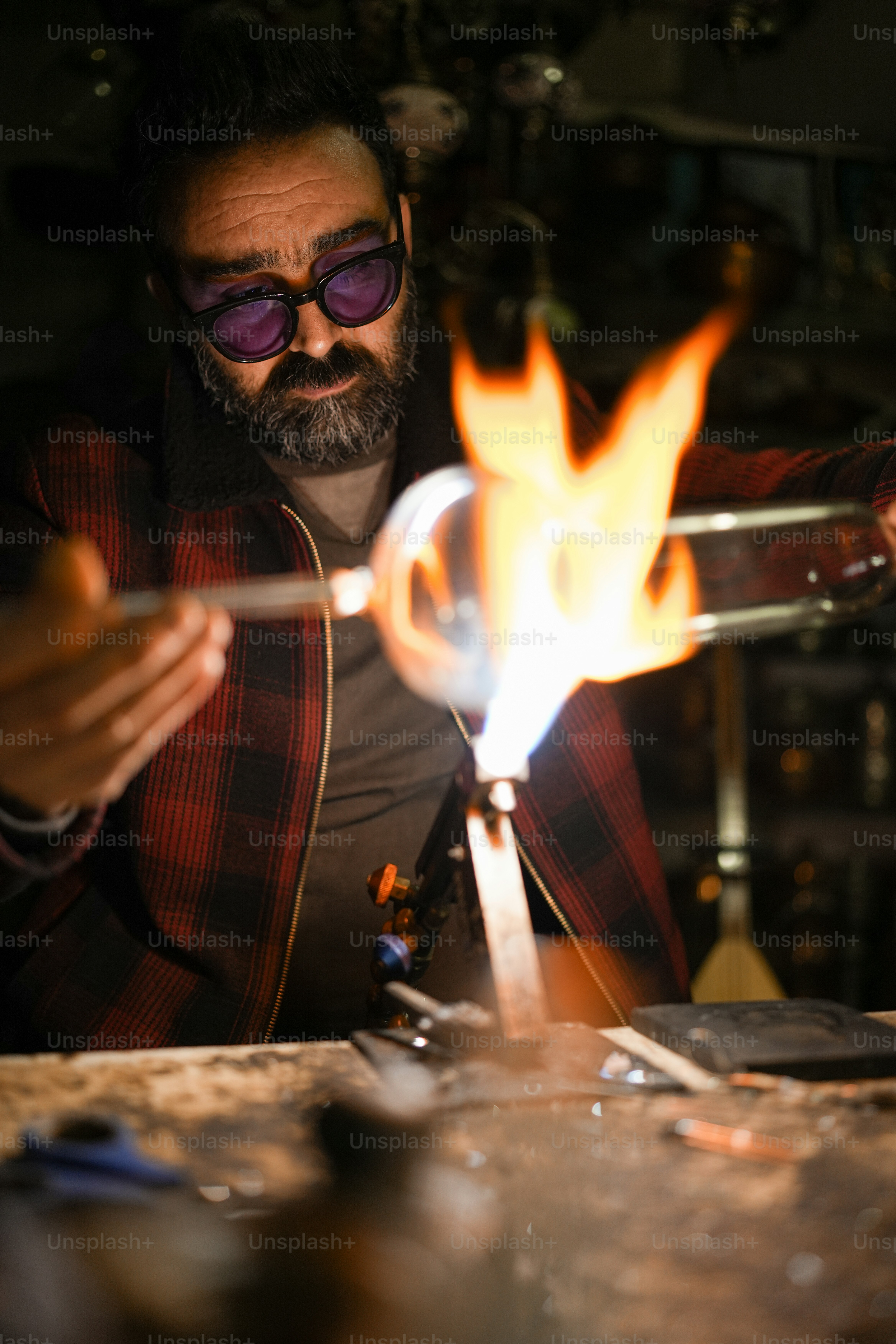 A man in a red and black jacket lighting a candle photo – Glass art ...
