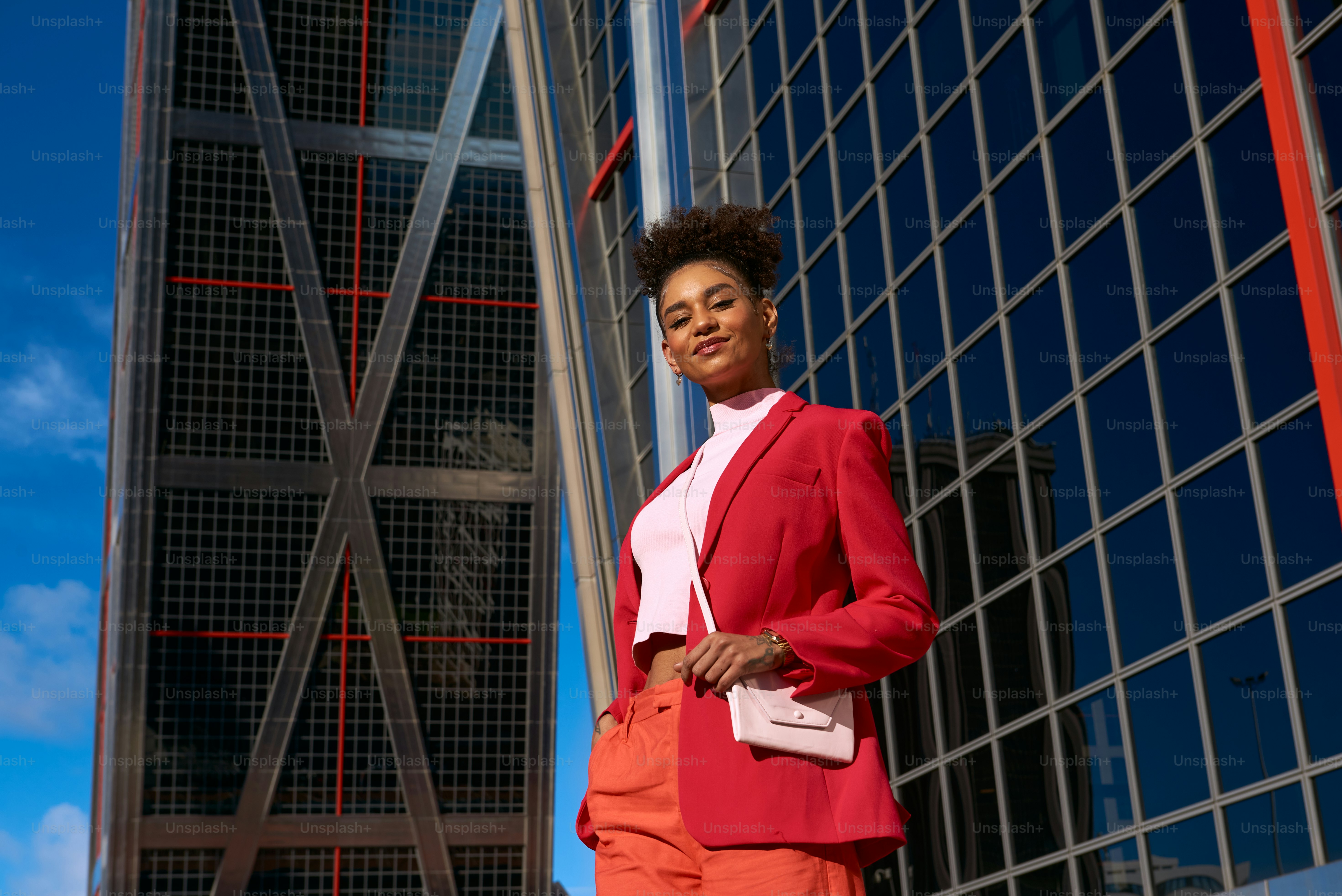 A woman standing in front of a tall building photo – Business woman ...