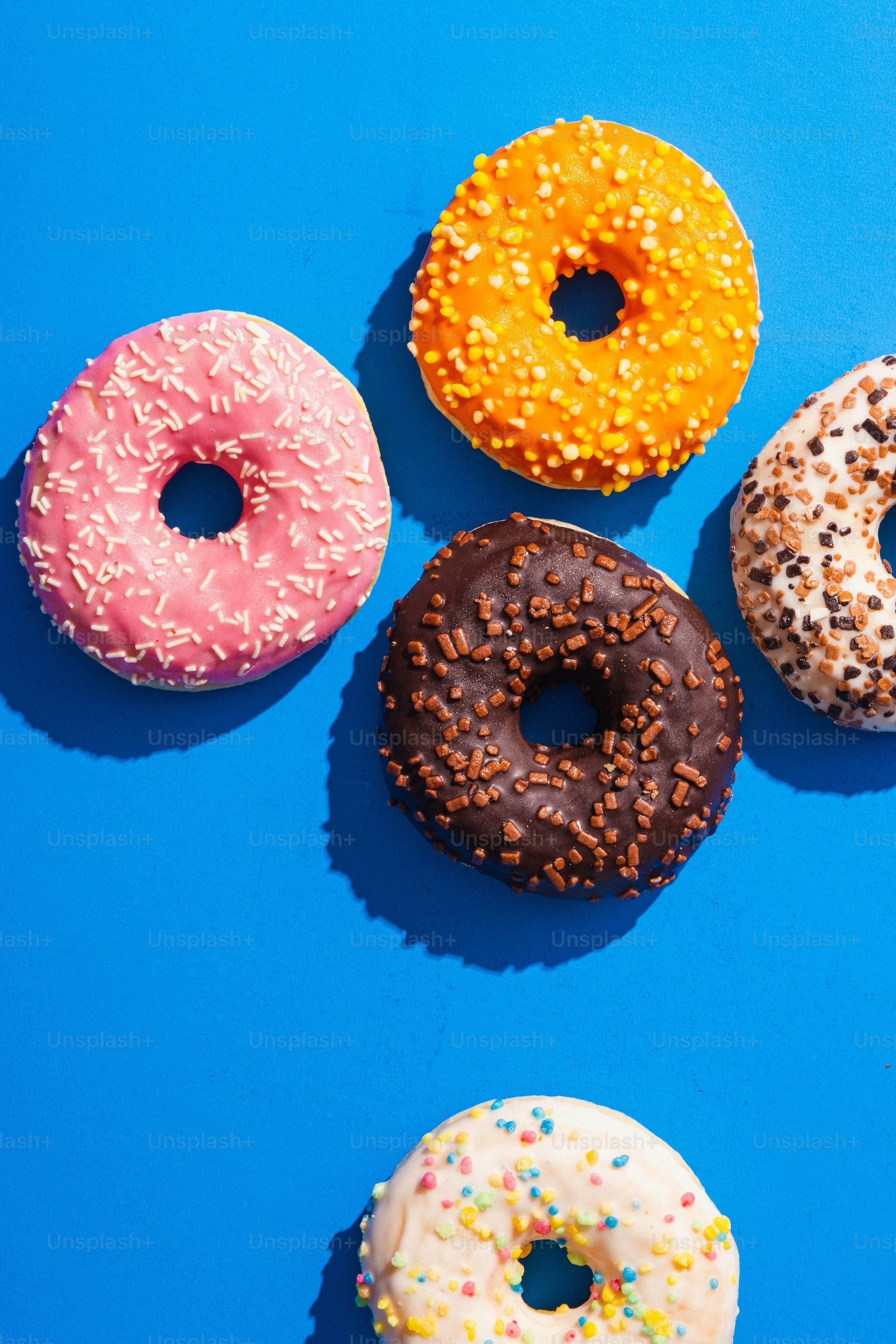 A group of four donuts sitting on top of a blue surface photo ...