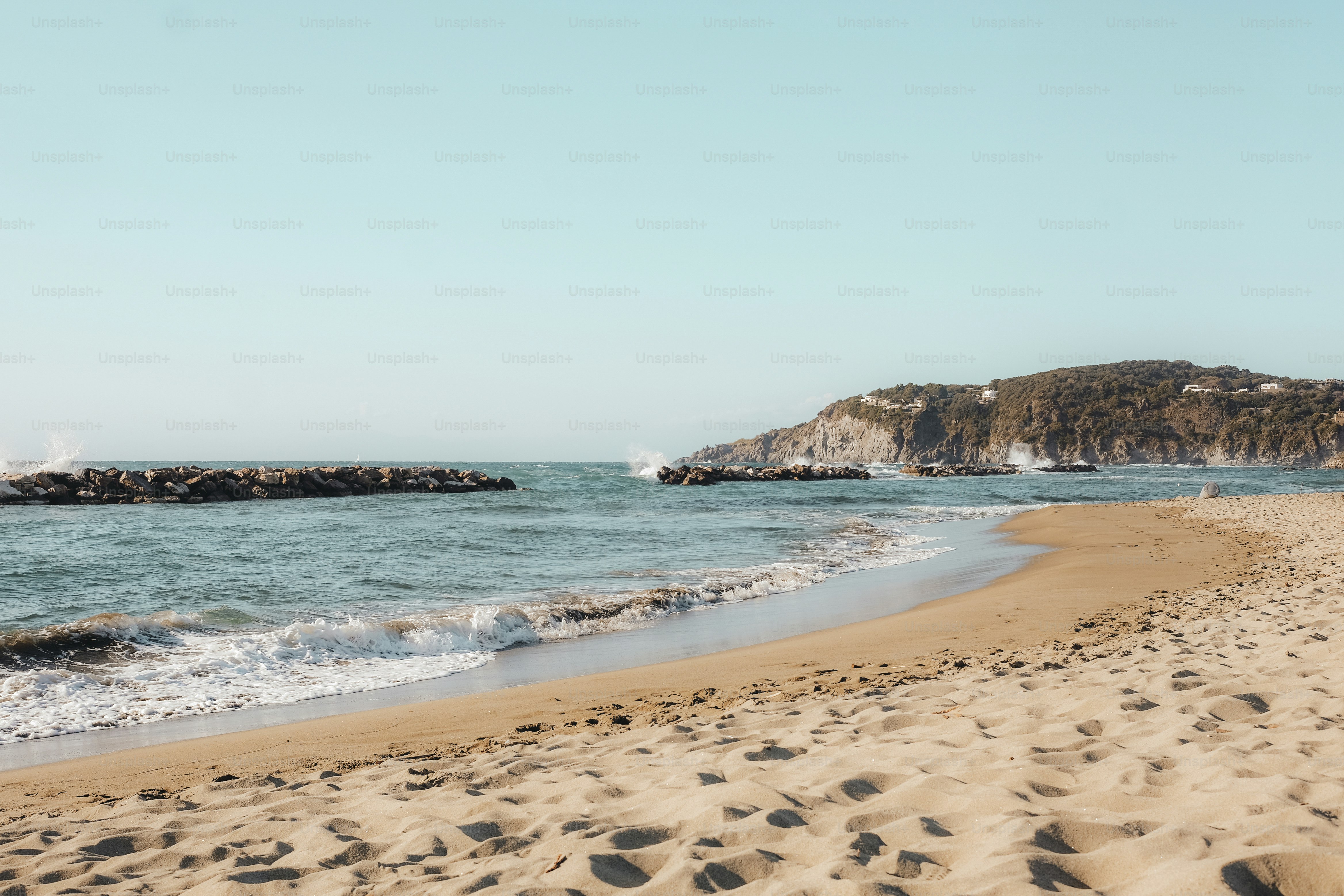A sandy beach with waves coming in to shore photo – Seashore Image on ...