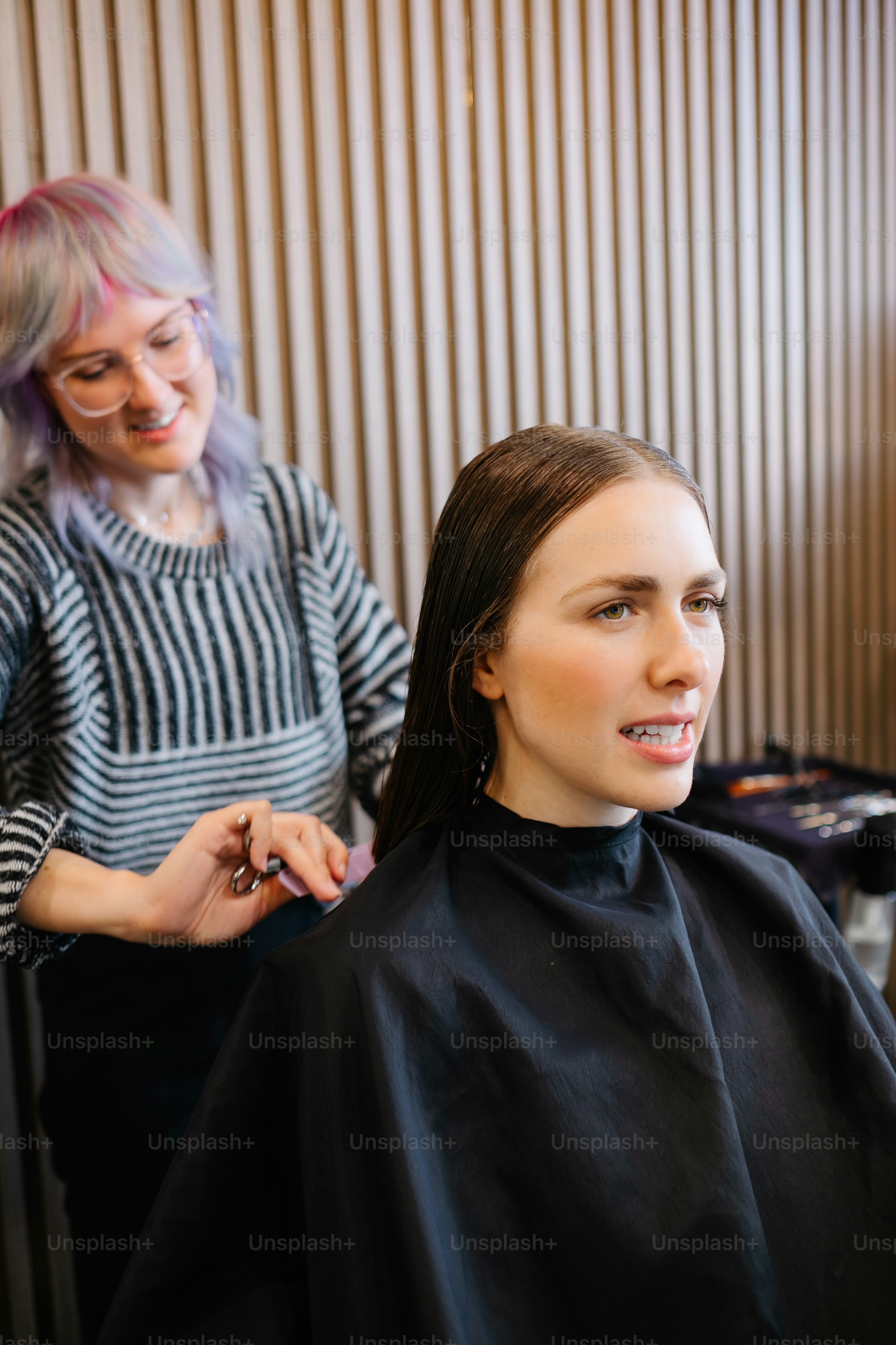 A woman sitting in a chair getting her hair cut photo – Professional ...