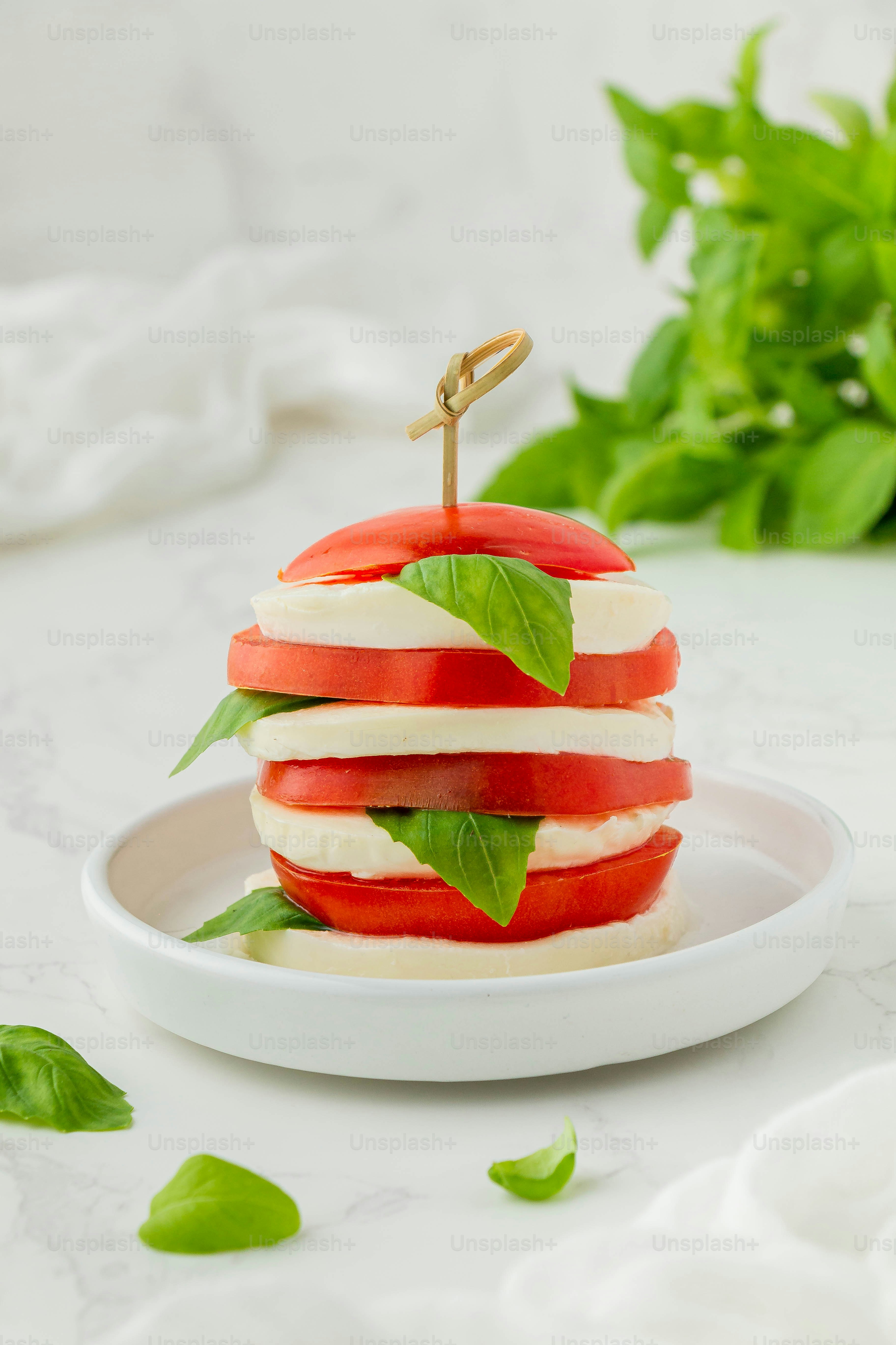 A white plate topped with an apple covered in cheese and tomato slices ...