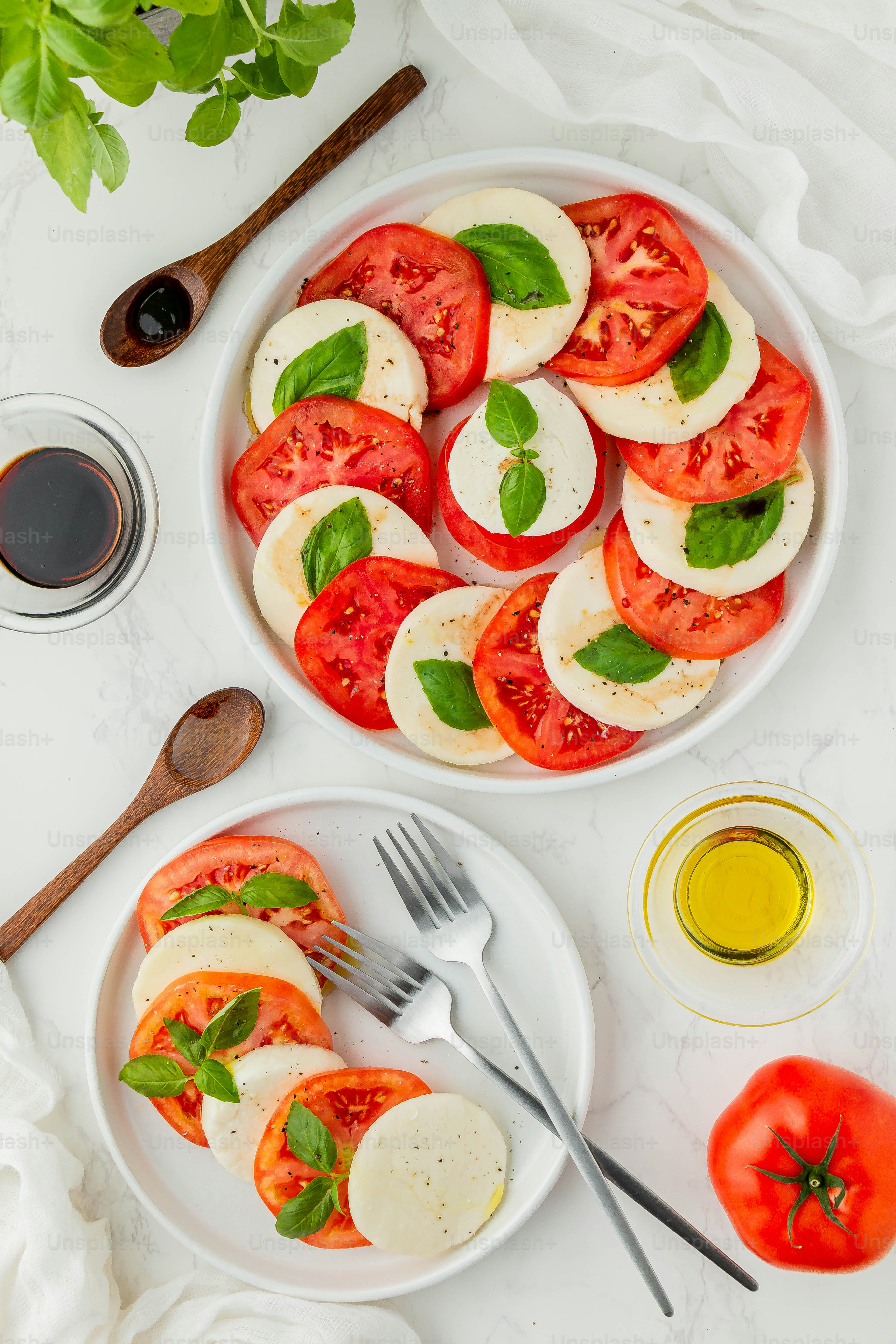Um prato branco coberto com tomates fatiados ao lado de um copo de ...