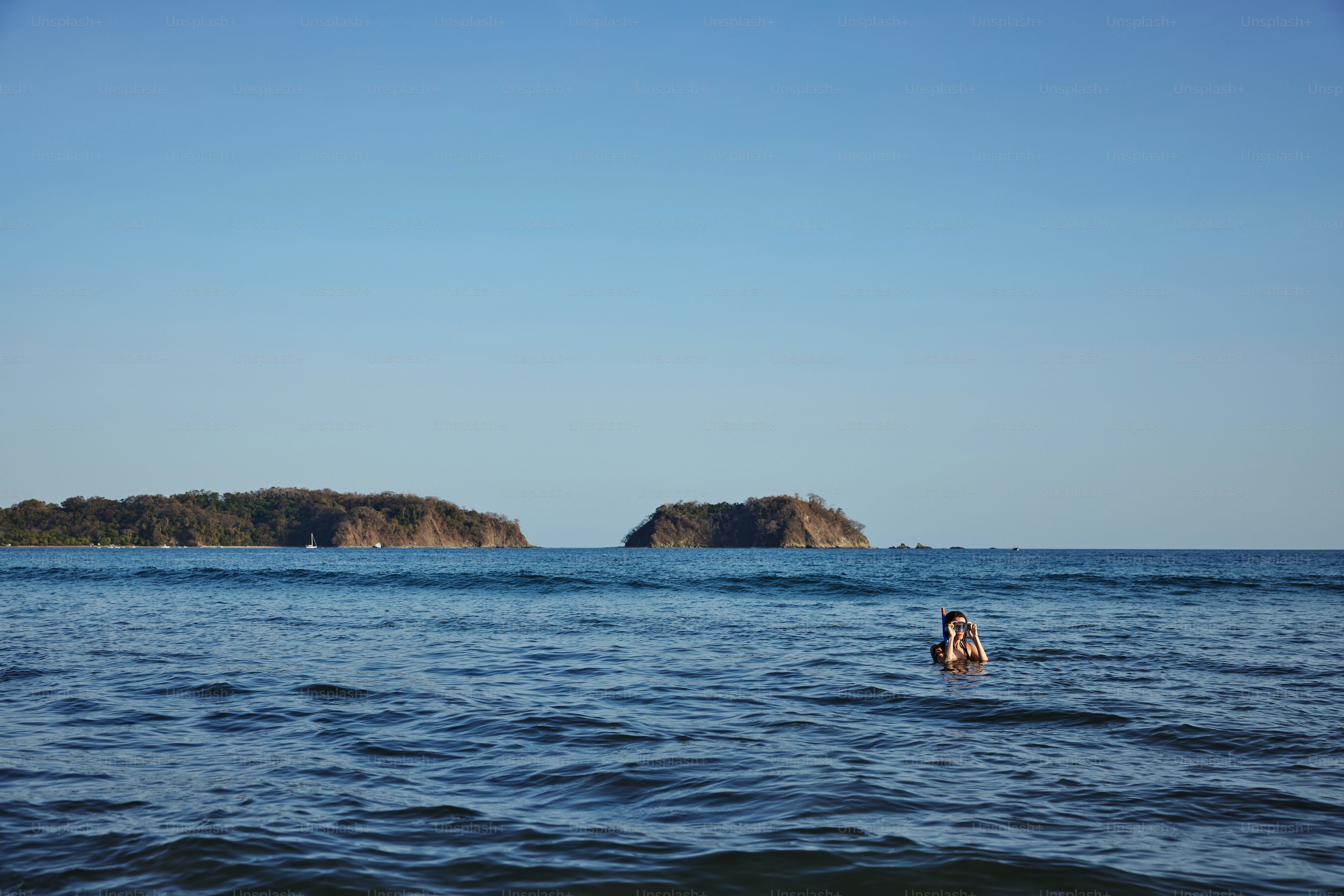 A person swimming in the ocean near a small island photo – Spring break ...