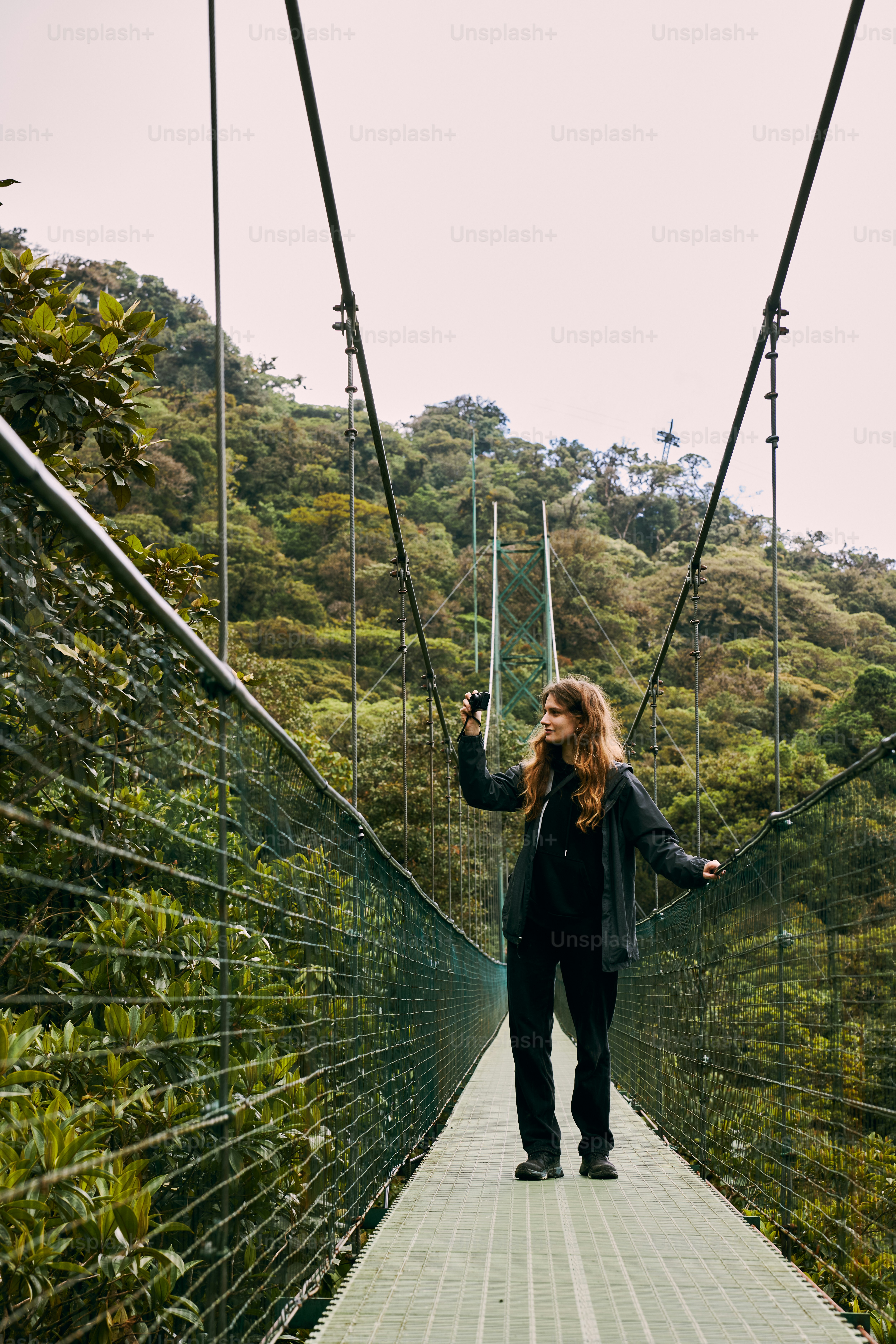 A woman is walking across a suspension bridge photo – Bmp photo Image ...