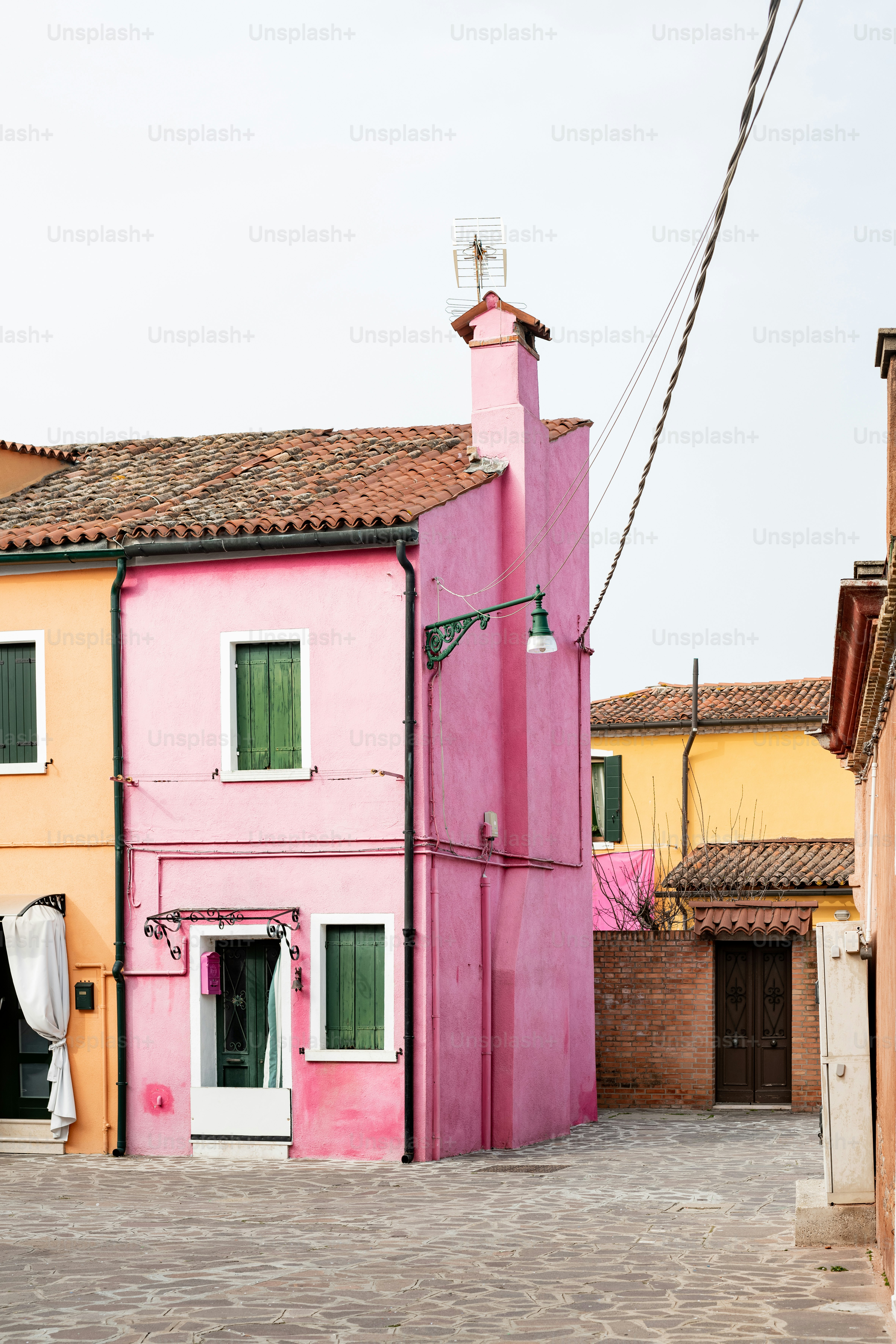 A pink and yellow building with a red roof photo – Italy Image on Unsplash